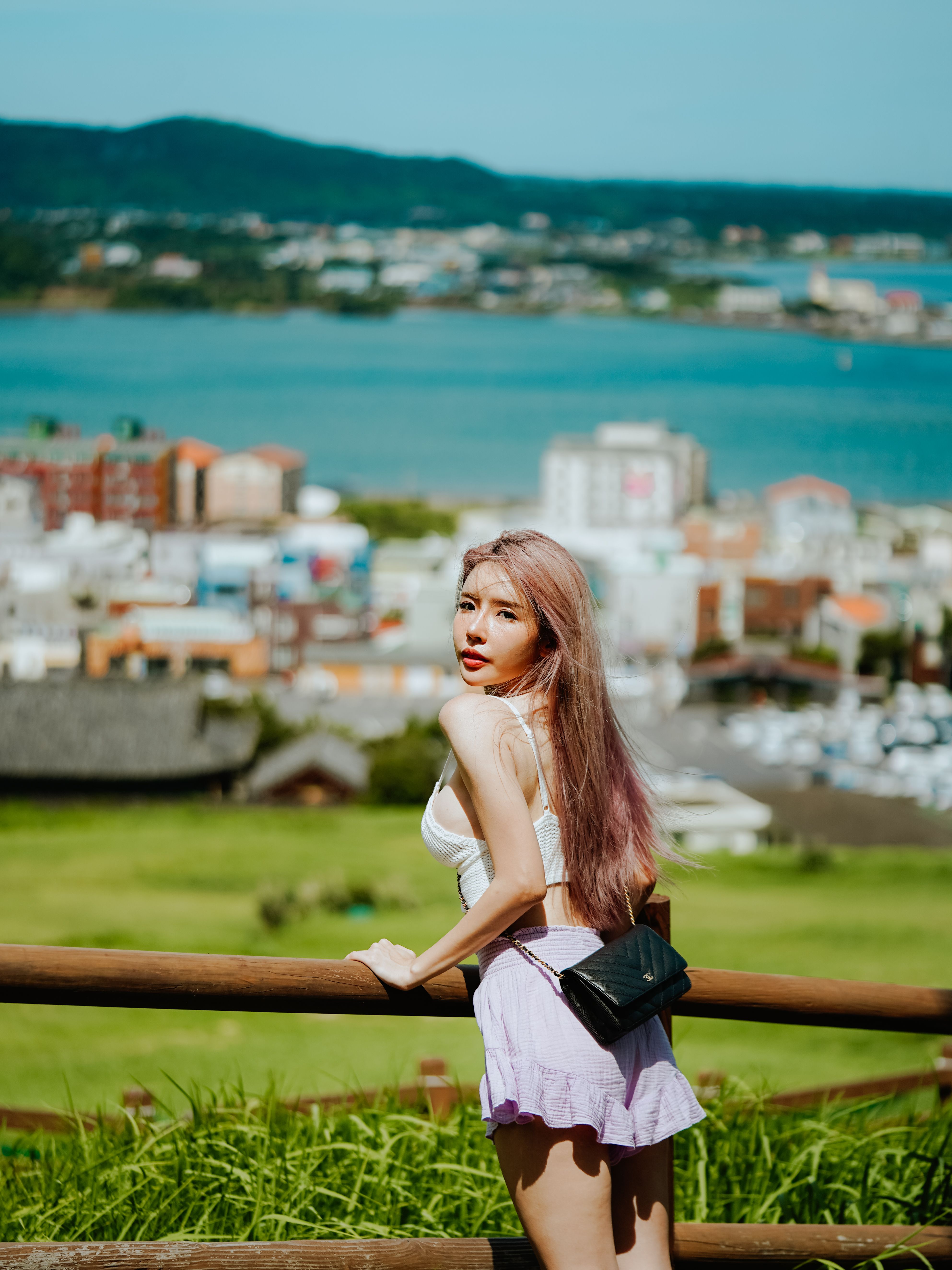Woman in Sundress Sitting on Wooden Boardwalk Railing · Free Stock Photo