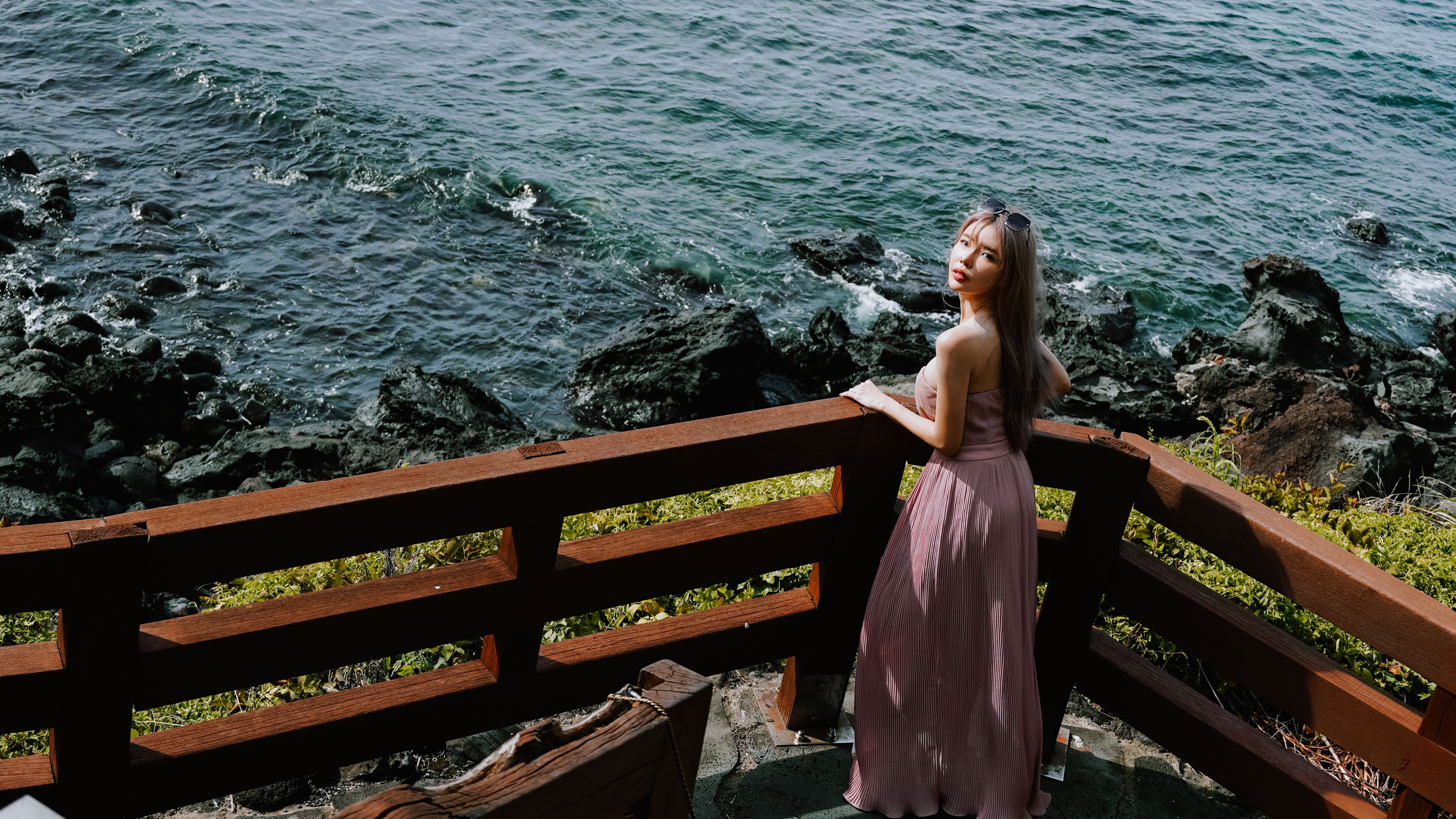 Woman in Sundress Sitting on Wooden Boardwalk Railing · Free Stock Photo