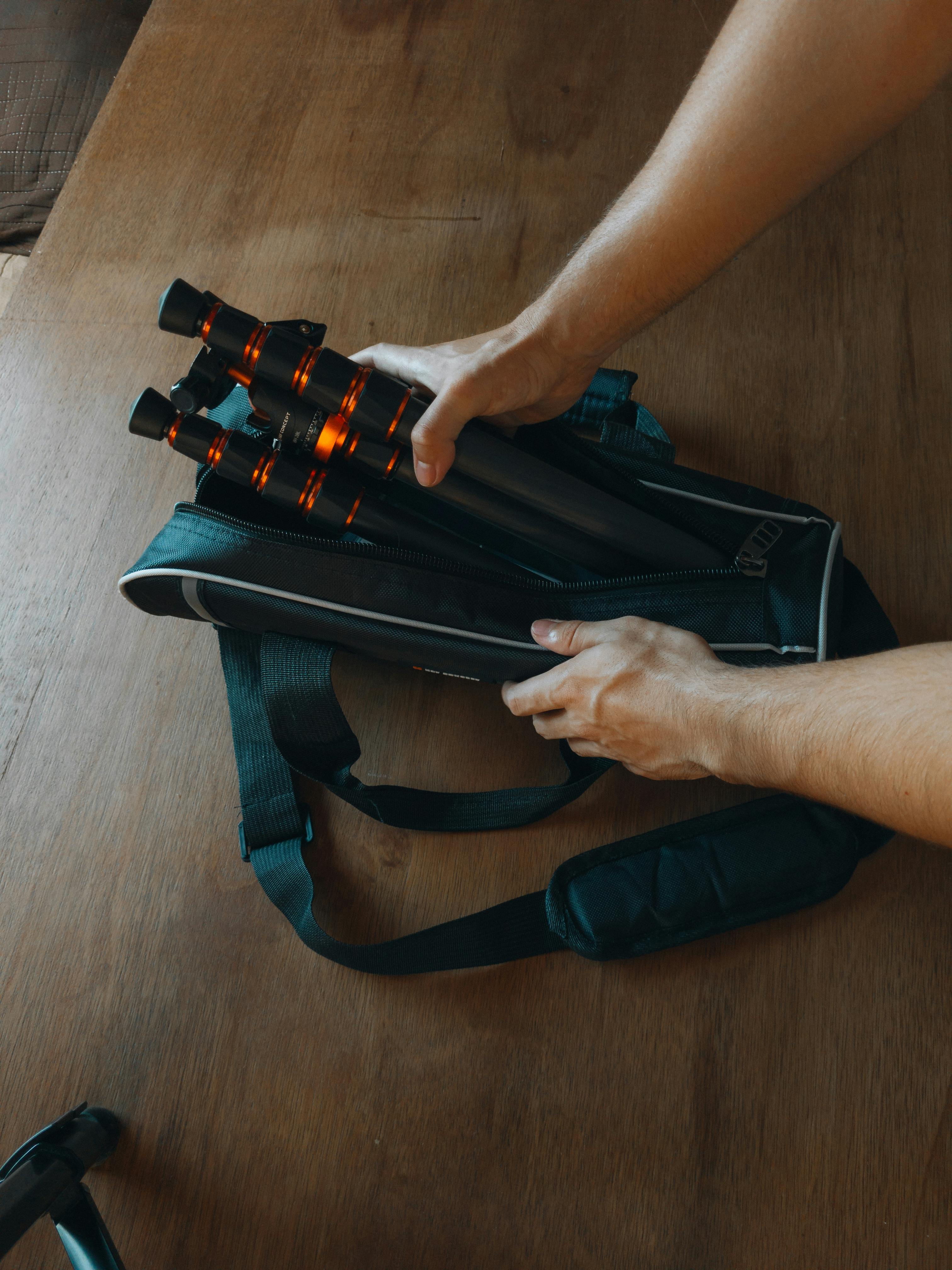 Close-up of Man Unpacking Bag with Tripod · Free Stock Photo