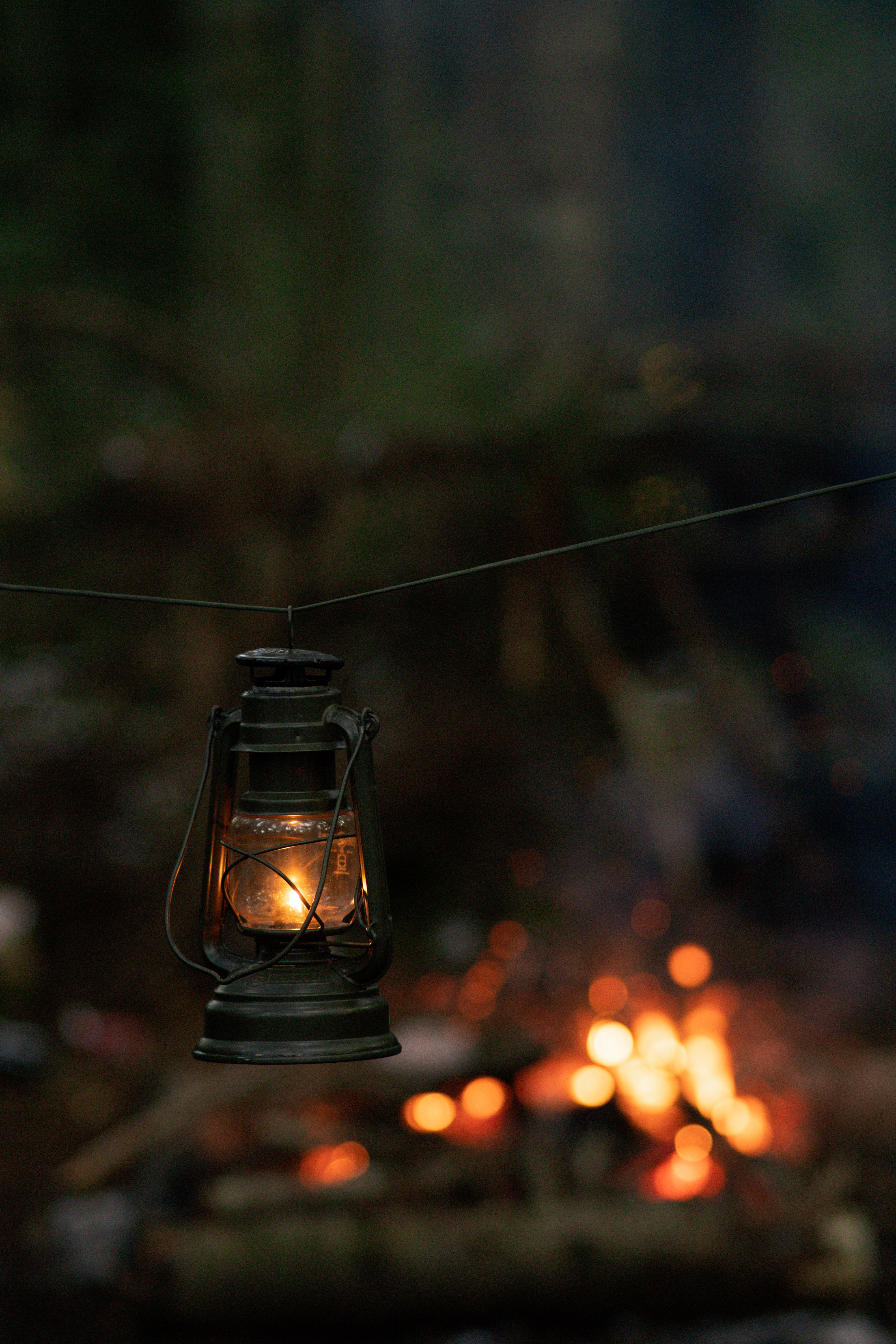 A lantern hanging from a rope in front of a campfire · Free Stock Photo