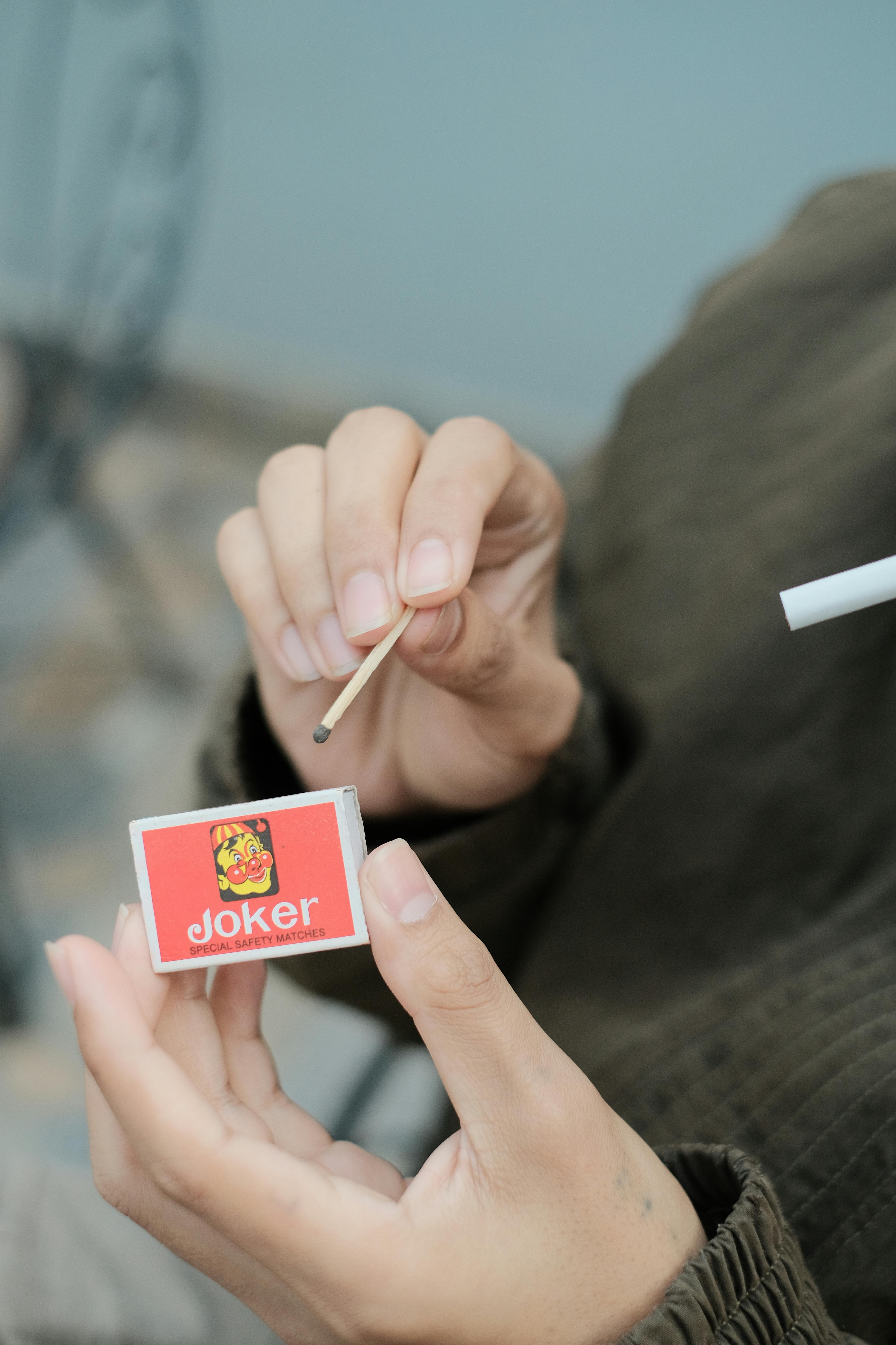 Close-up of Man Holding a Matchbox and a Match · Free Stock Photo