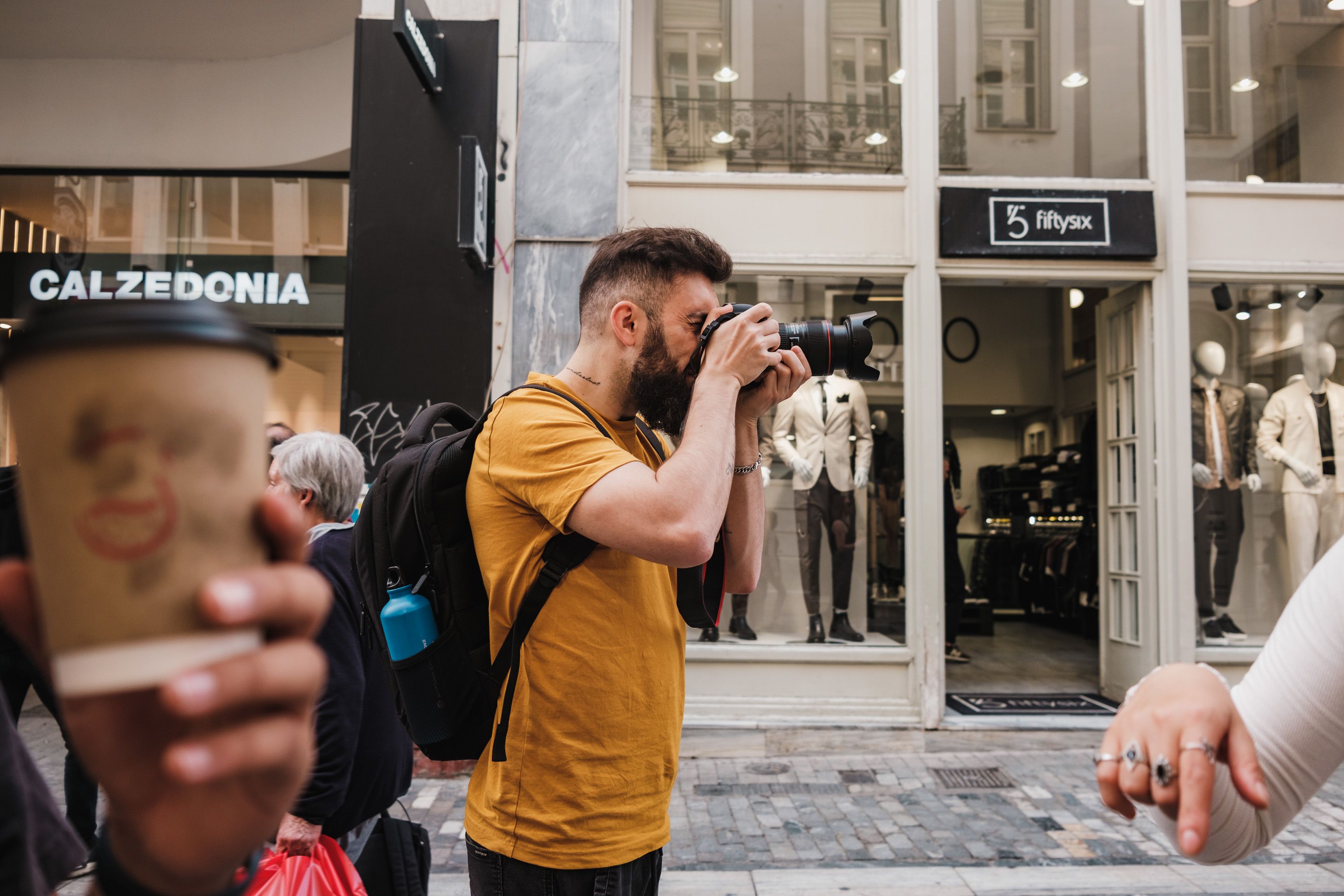 Man Photographing Walking on City Street · Free Stock Photo