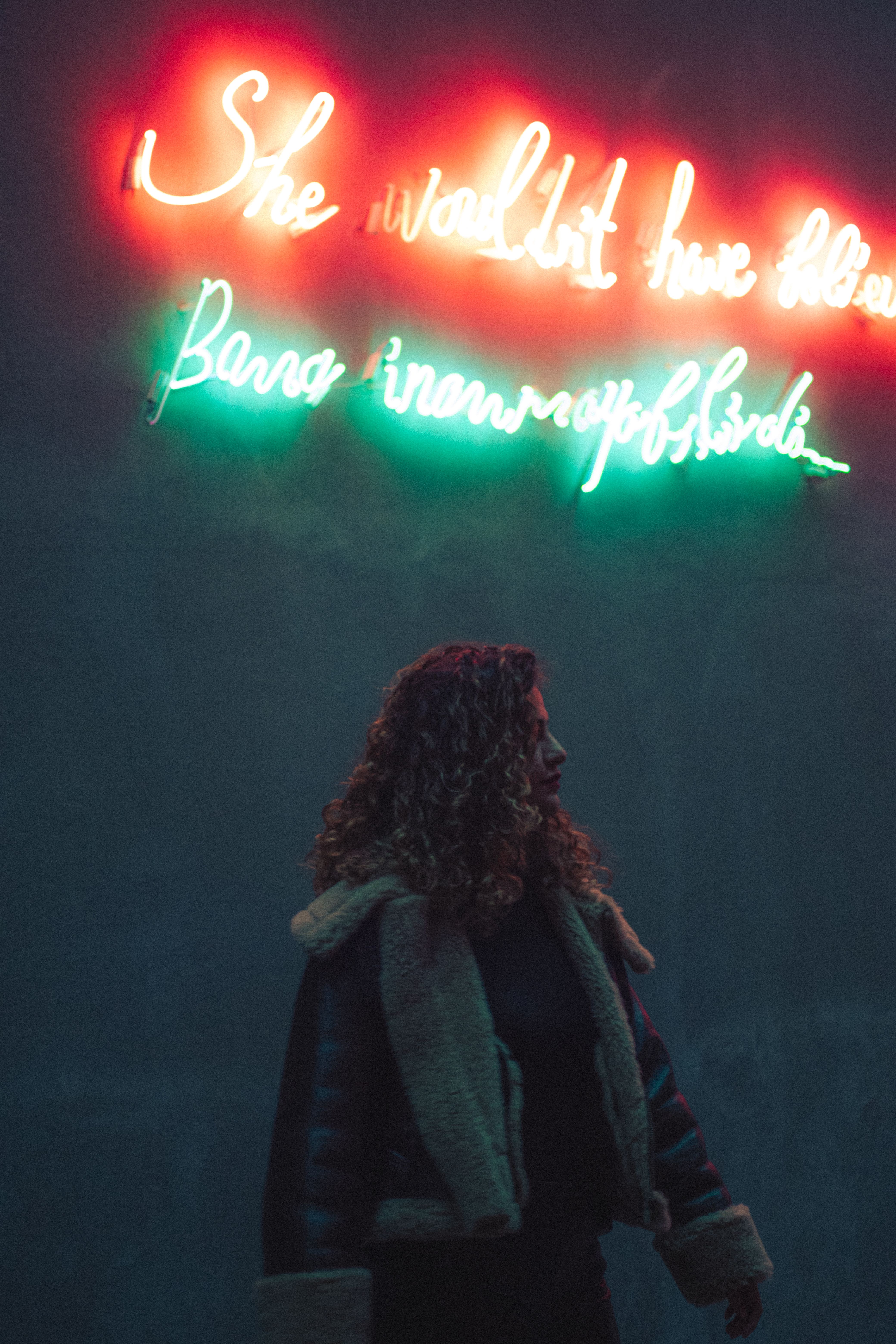 A Woman Standing Under a Neon Sign · Free Stock Photo