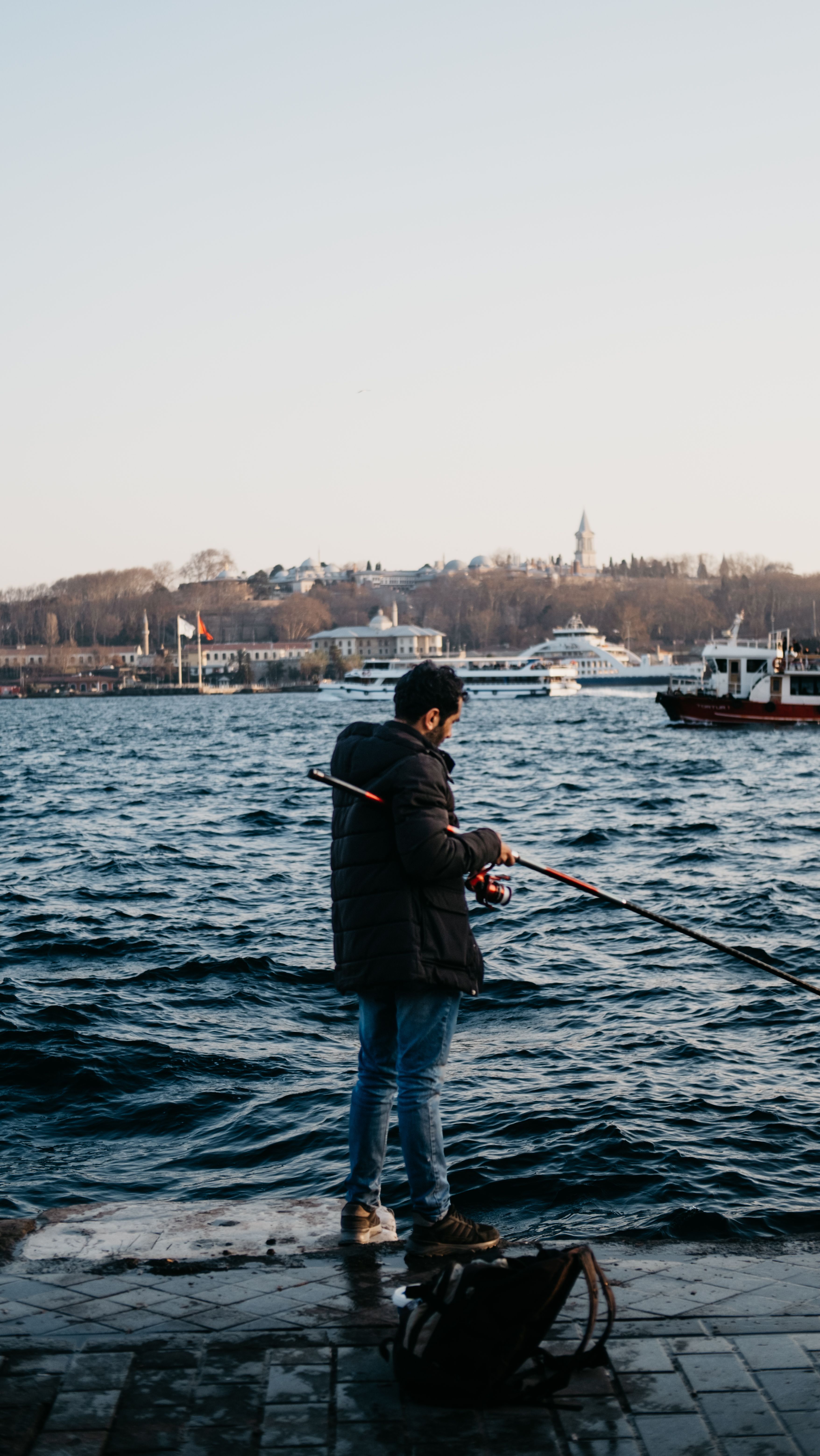 Fisherman in Jacket Standing with Fishing Rod · Free Stock Photo