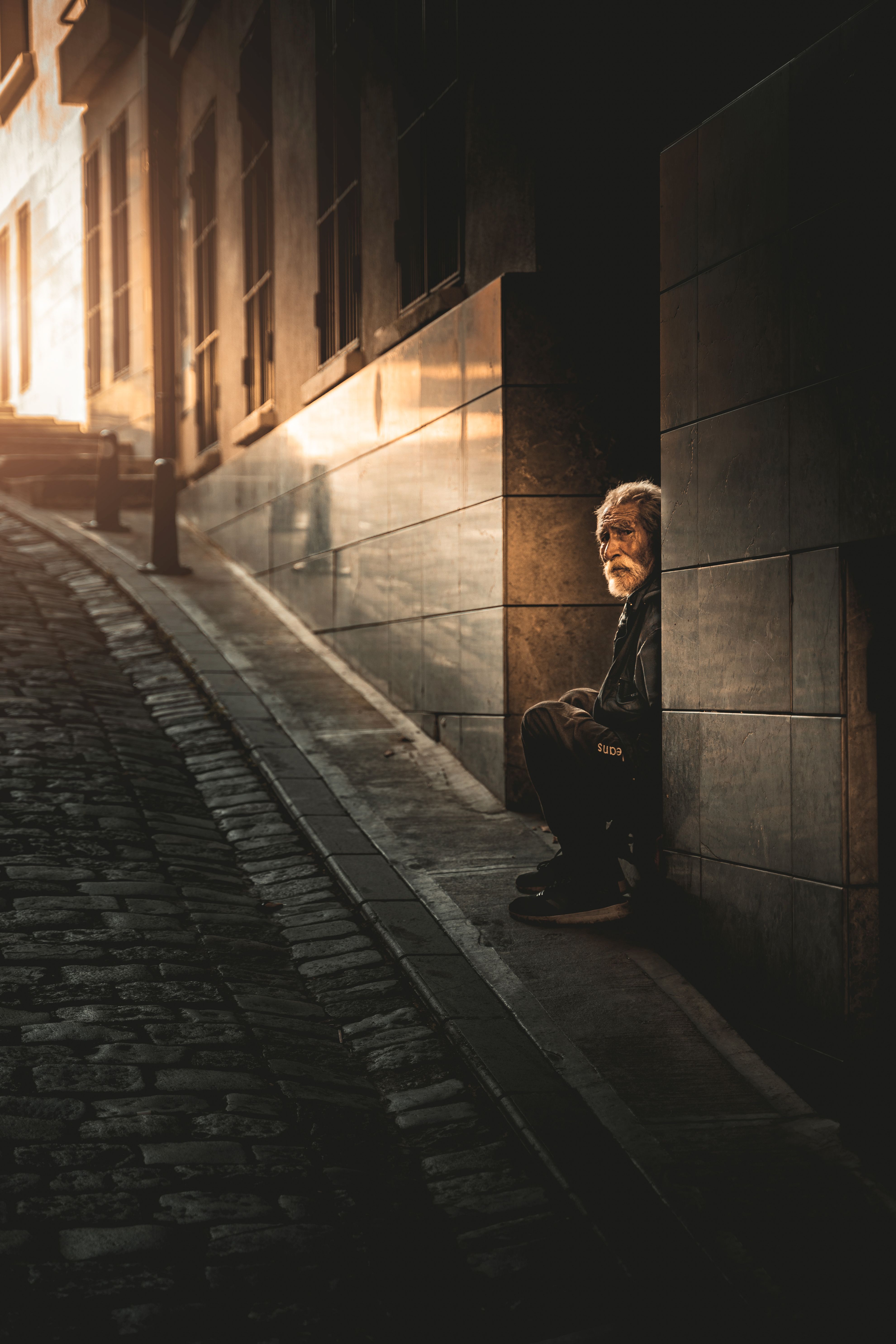 Senior Man Sitting on the Sidewalk at Dusk · Free Stock Photo