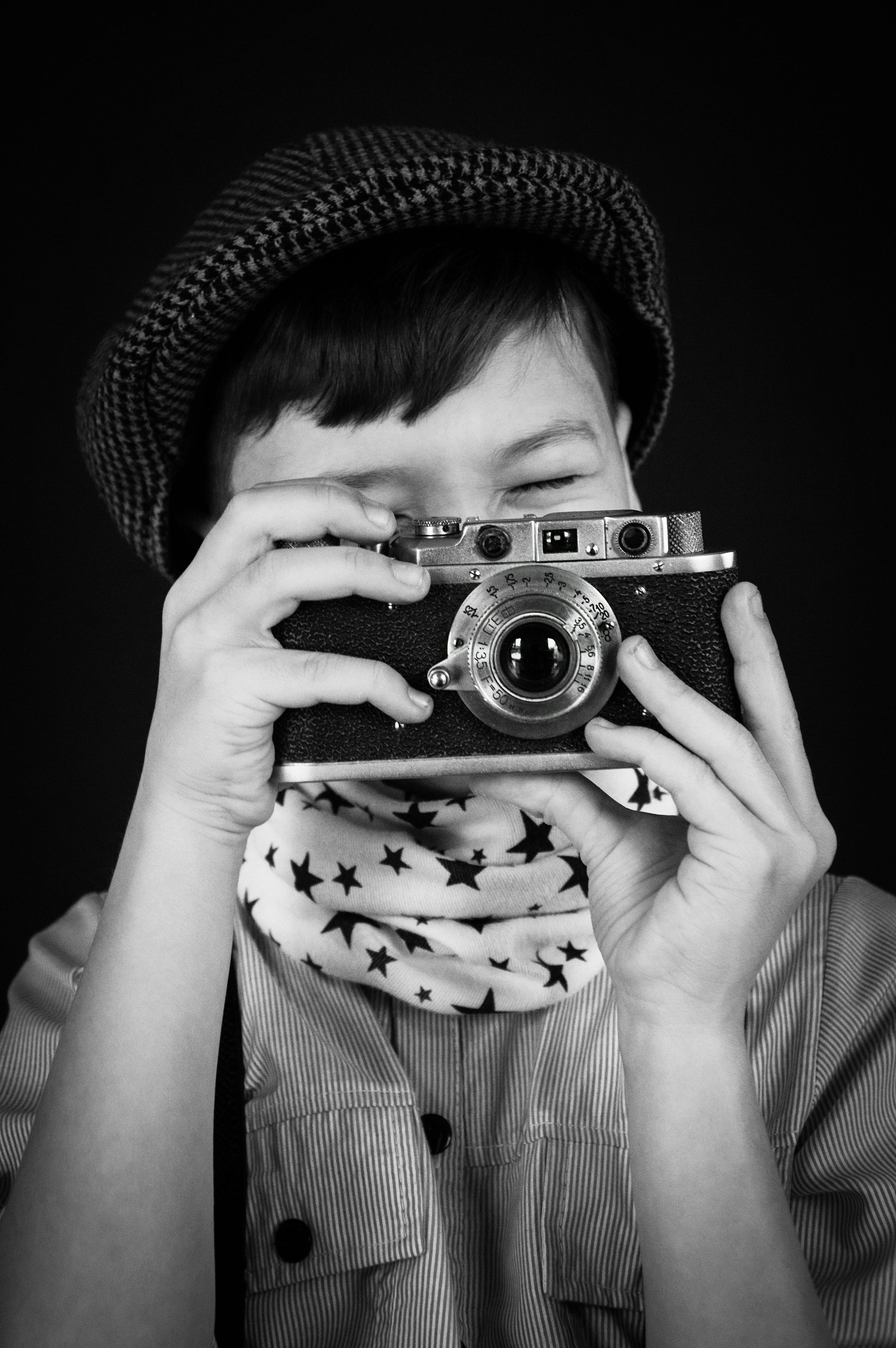 Boy Using Camera Near Green Leaf Plants · Free Stock Photo