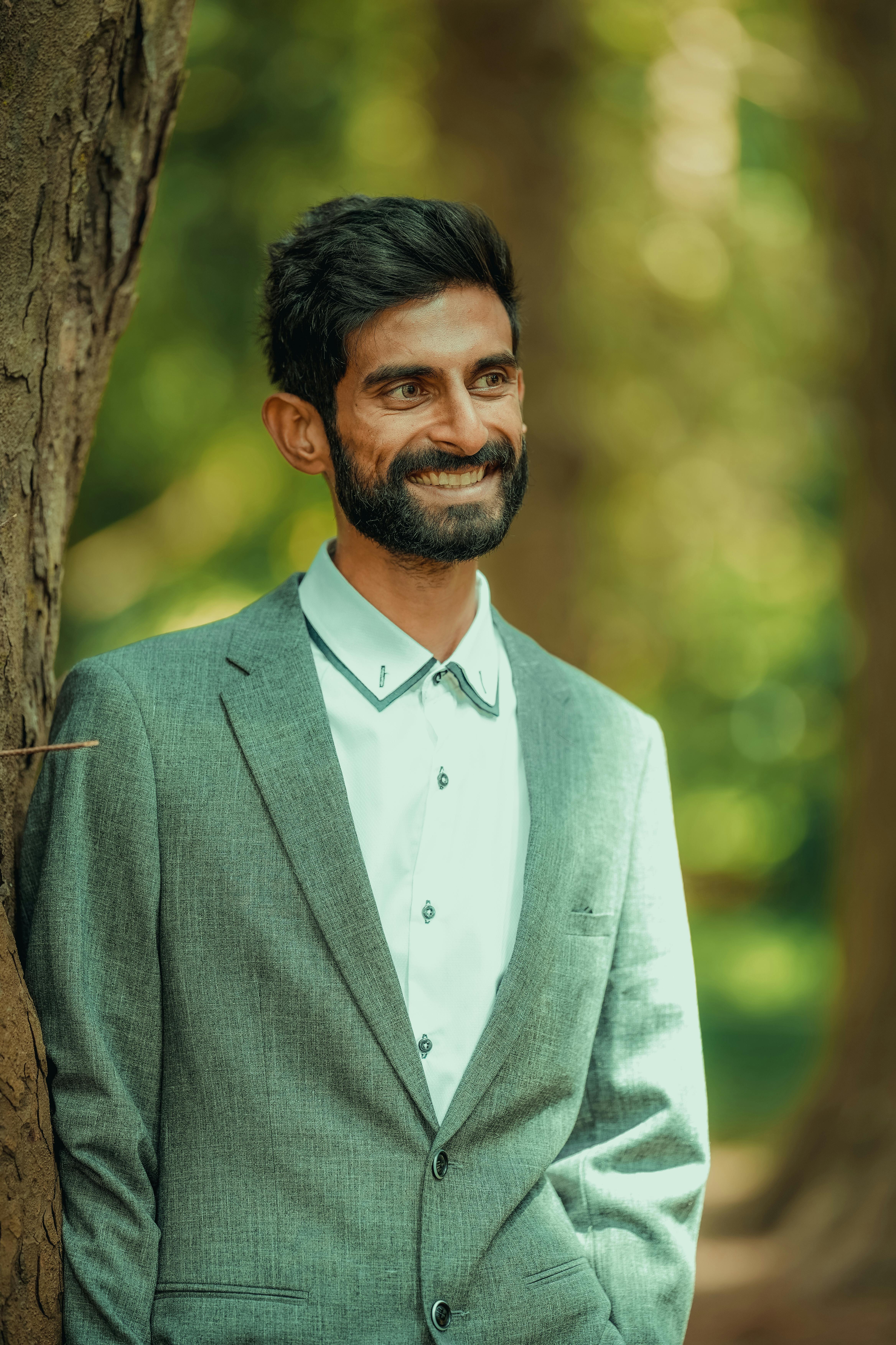 Smiling Man in Suit Leaning on Tree · Free Stock Photo