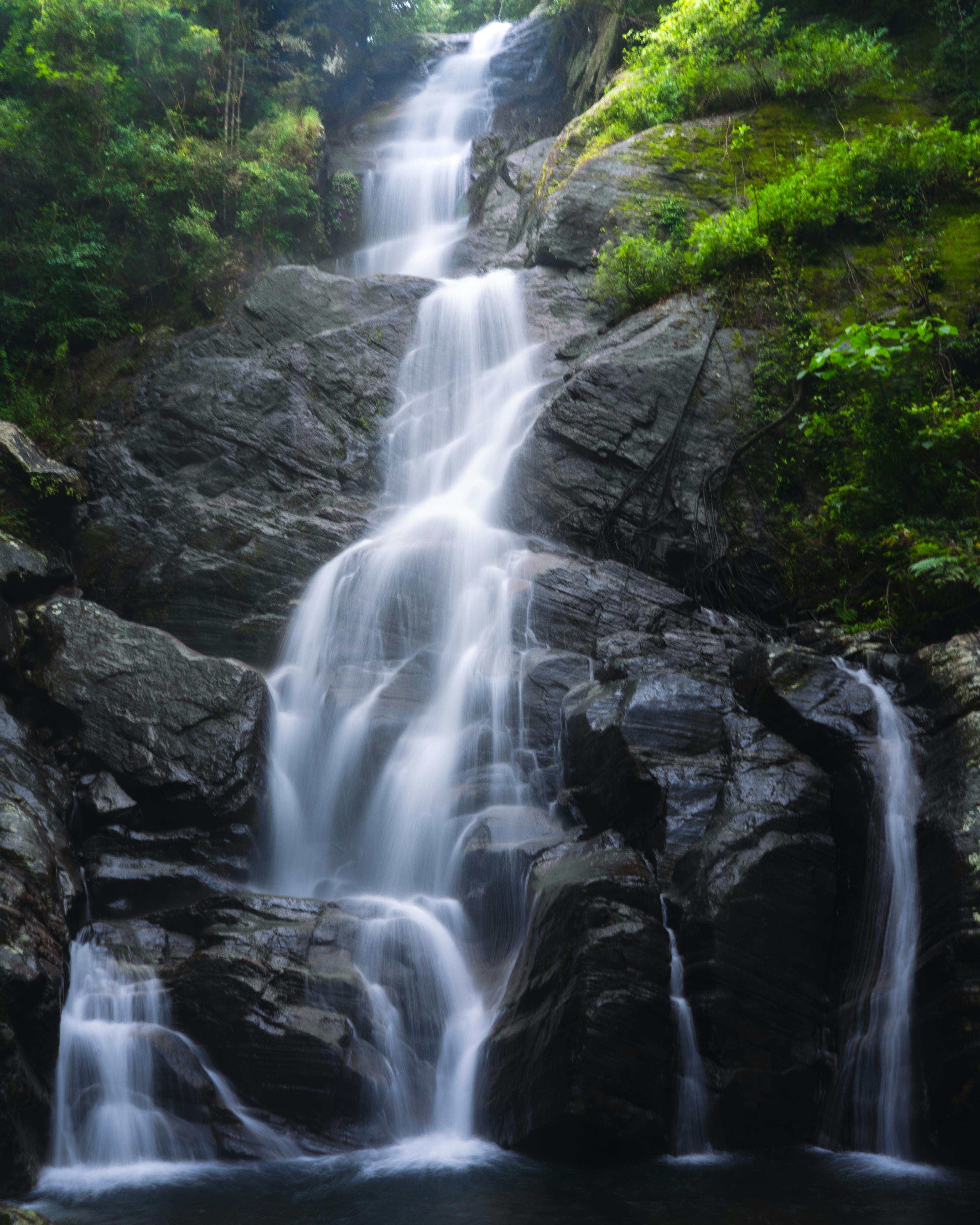 Waterfall Cascading Over Rocks in the Wilderness · Free Stock Photo