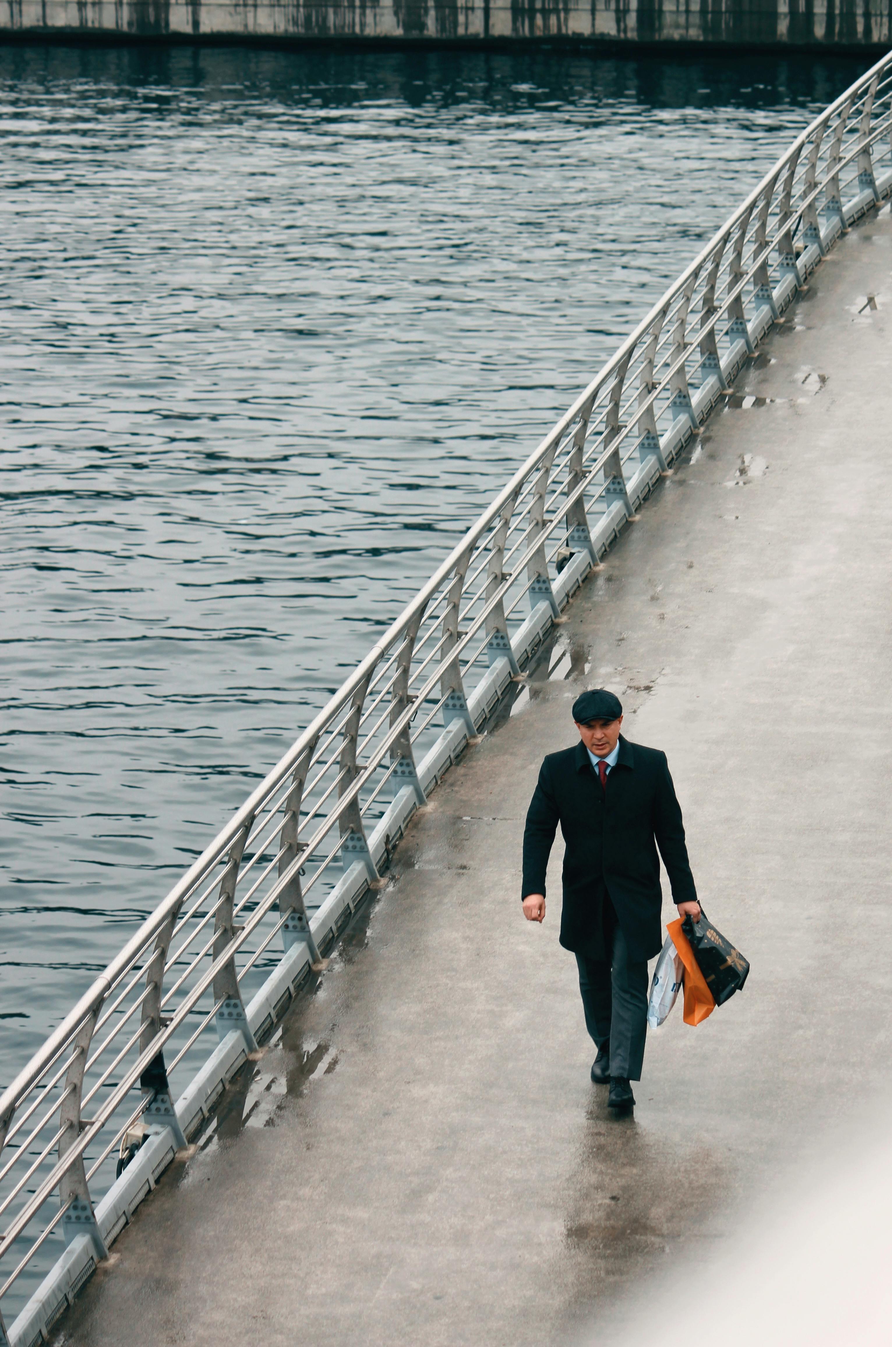 Man Walking on Bridge near Water · Free Stock Photo