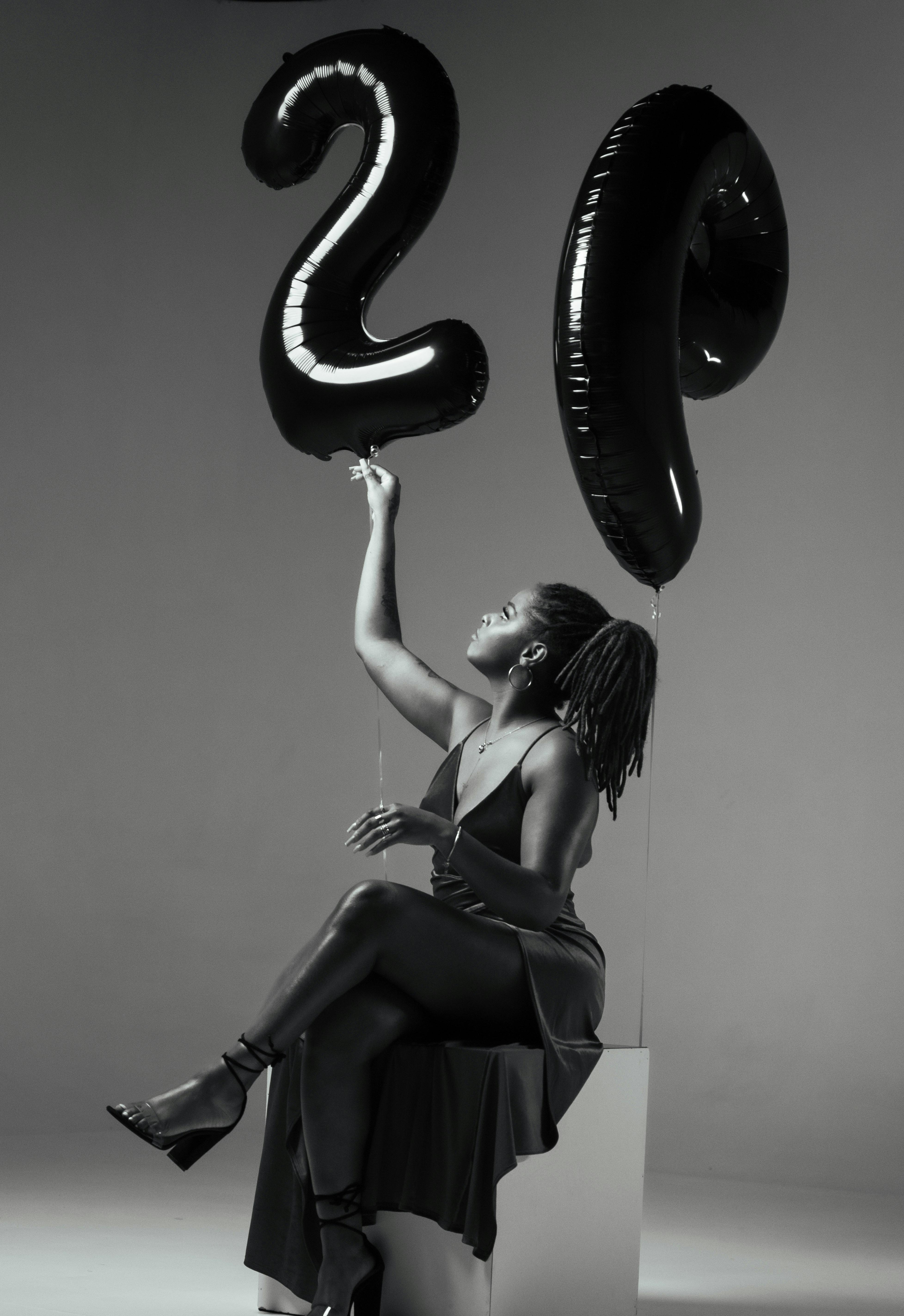 A Grayscale Photo of a Woman Sitting on the Block with Her Legs Crossed ...