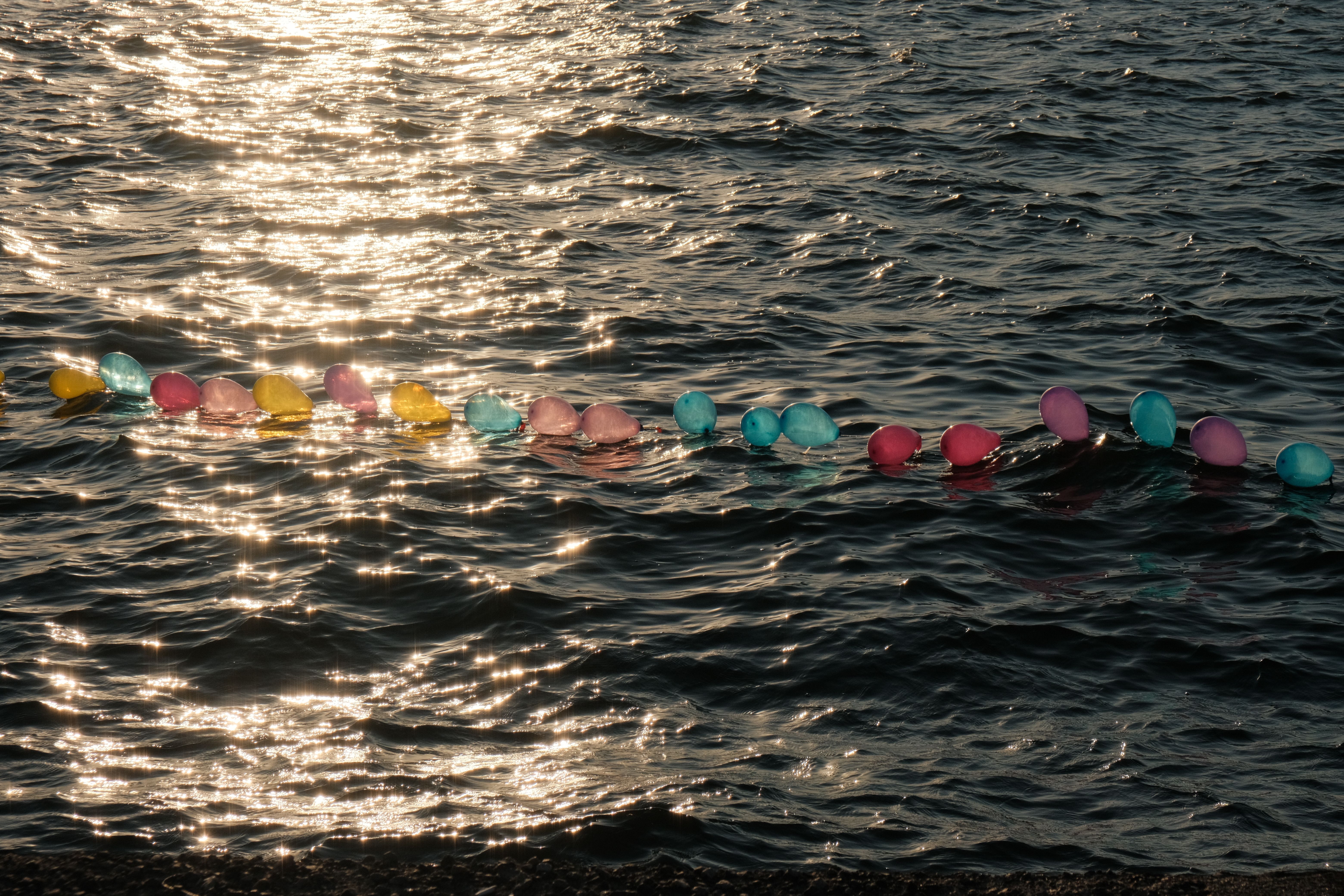String of Balloons Floating on Sea Surface · Free Stock Photo