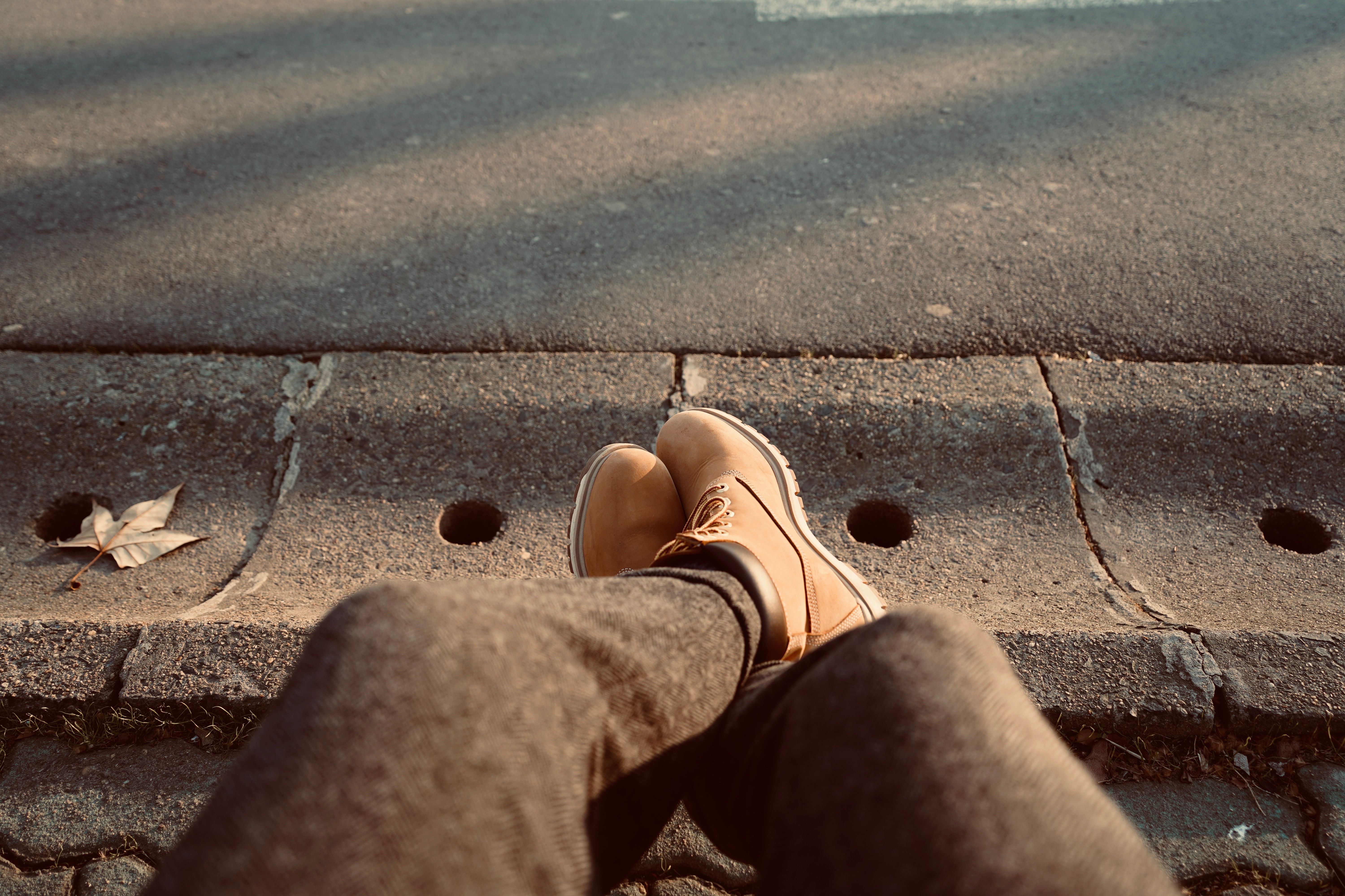 Person Wearing Brown Boot Sitting Beside a Gutter · Free Stock Photo