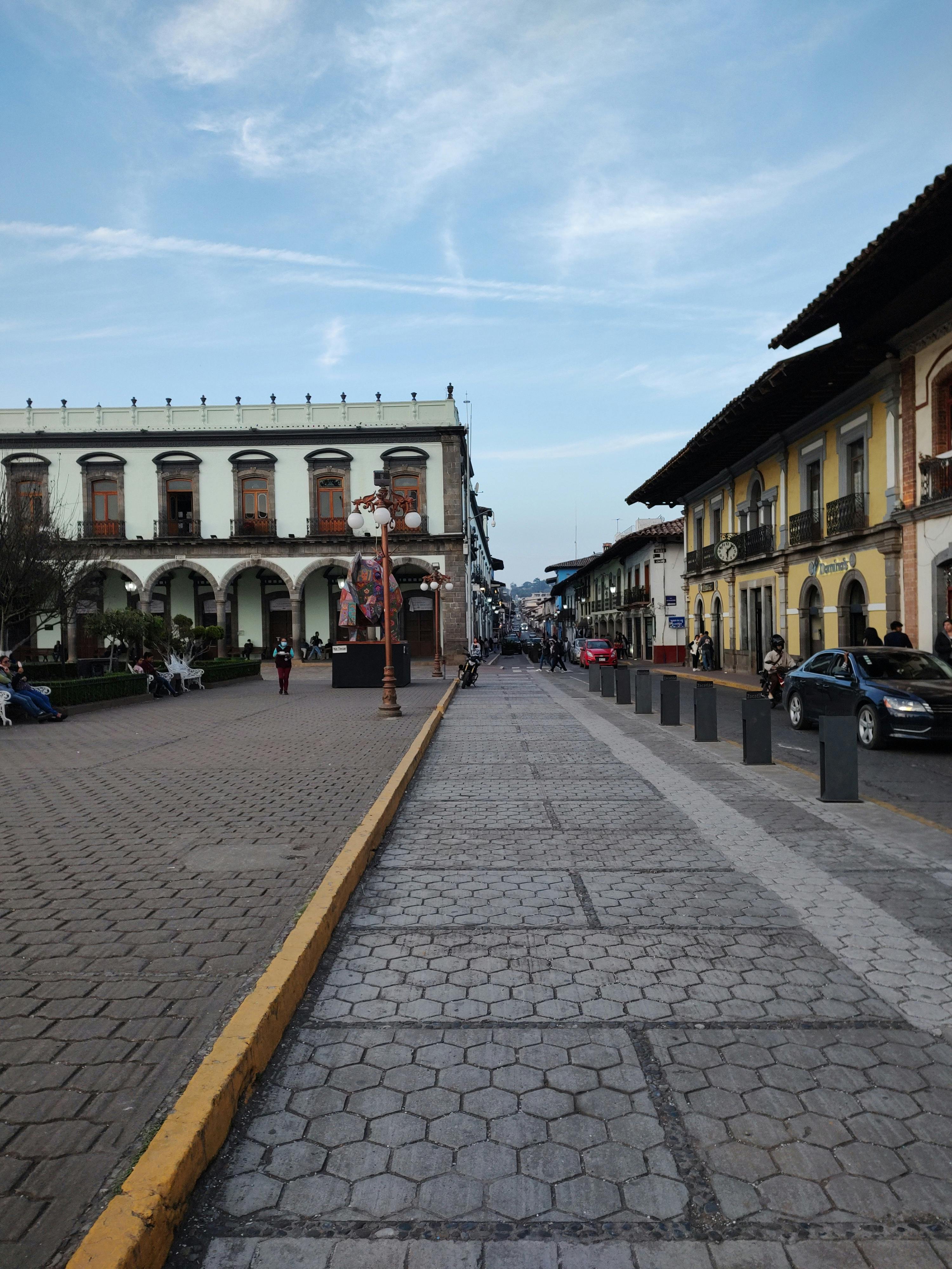 A Cobblestone Street Between Concrete Buildings · Free Stock Photo