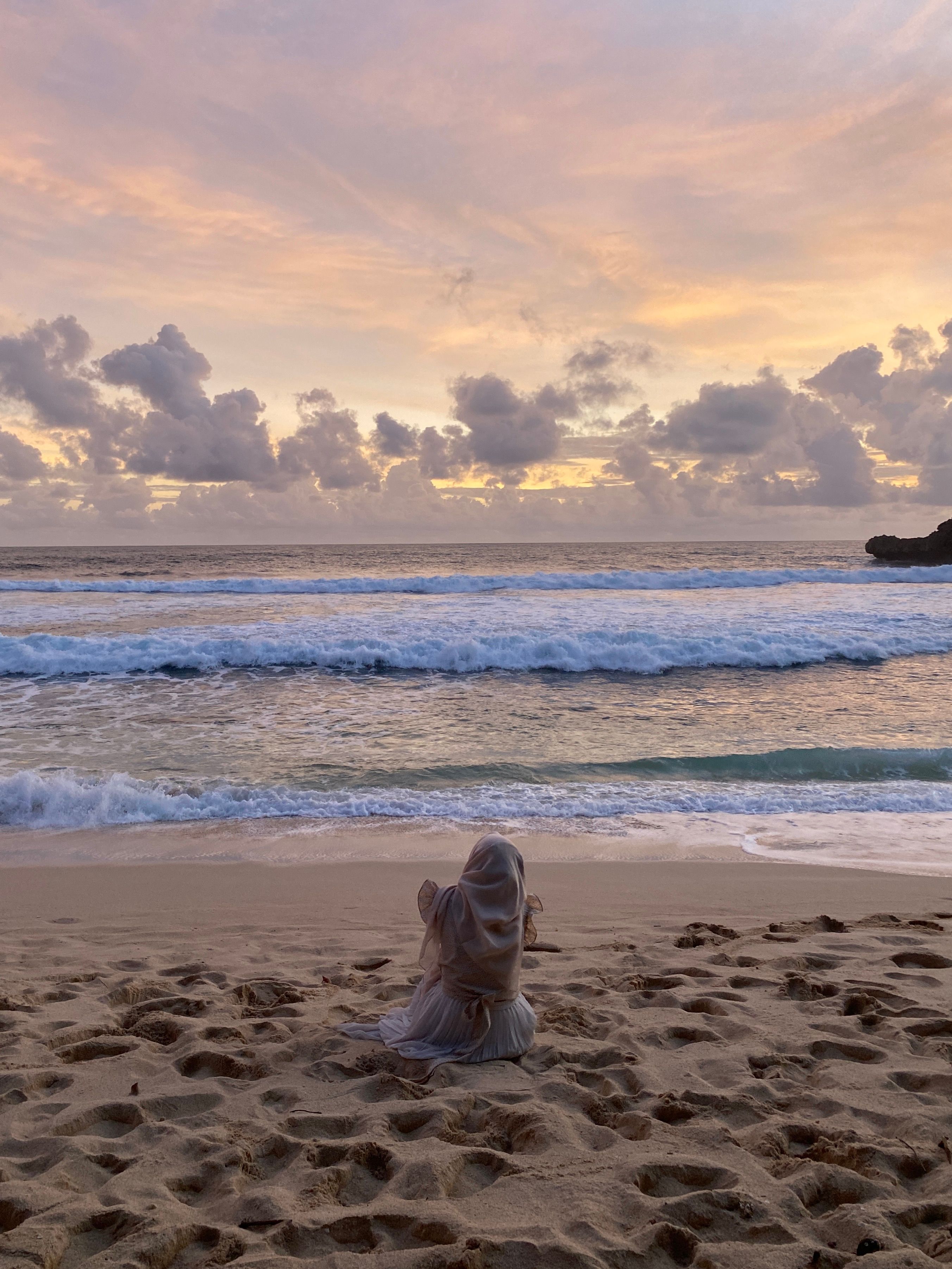 A woman sitting on the beach at sunset · Free Stock Photo