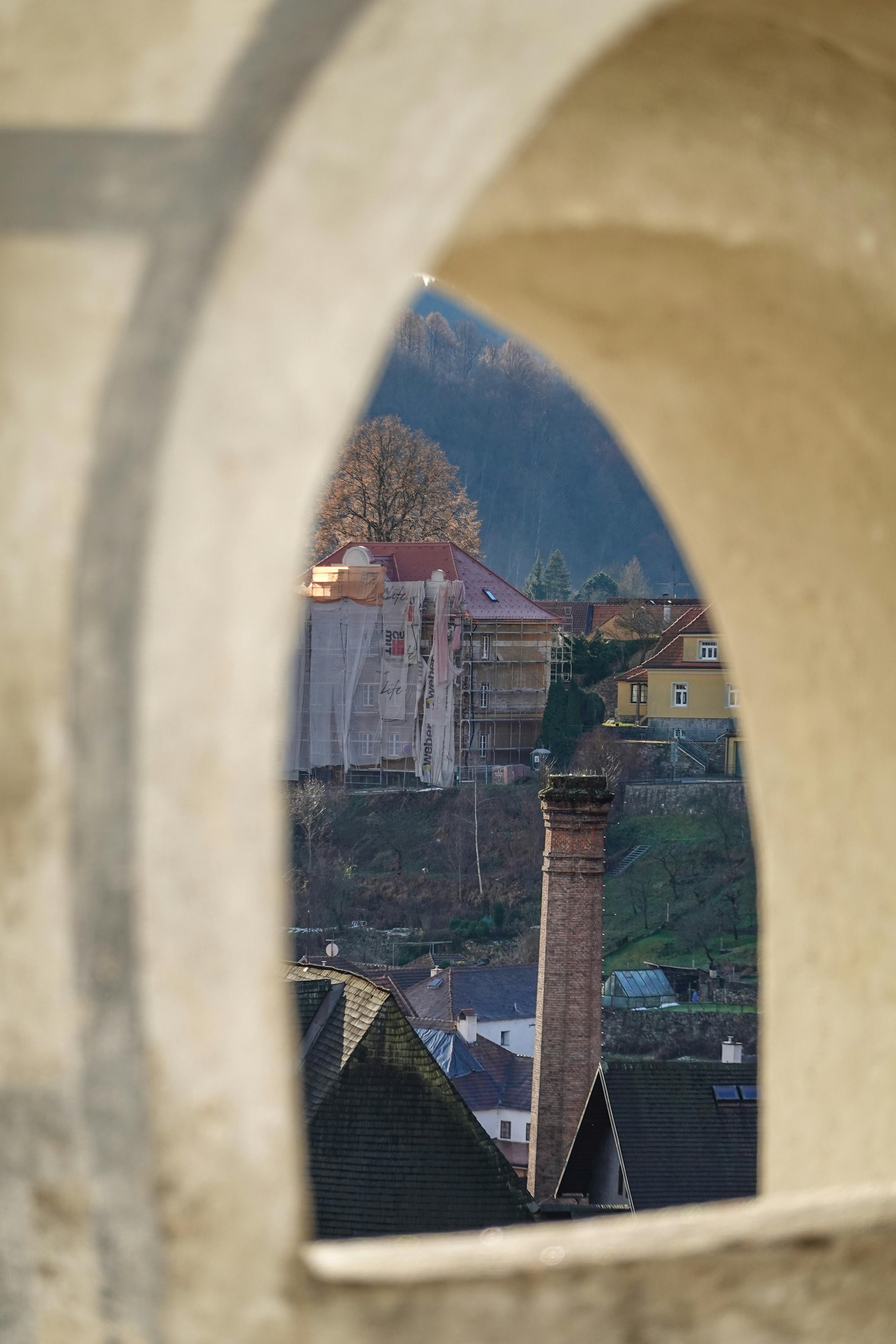 Old Factory Chimney Seen through a Window in Wall · Free Stock Photo