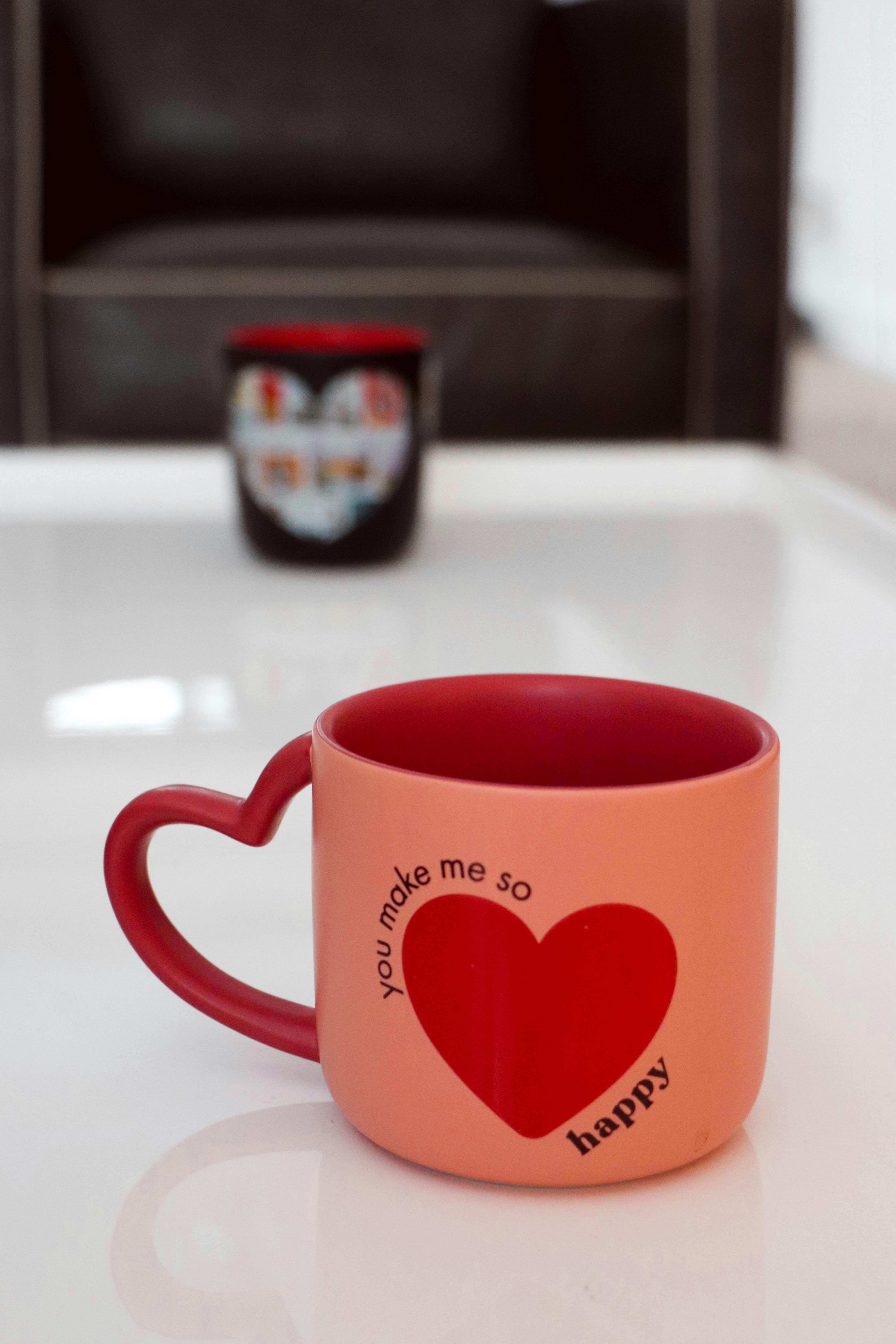A red heart shaped coffee mug sits on a table · Free Stock Photo