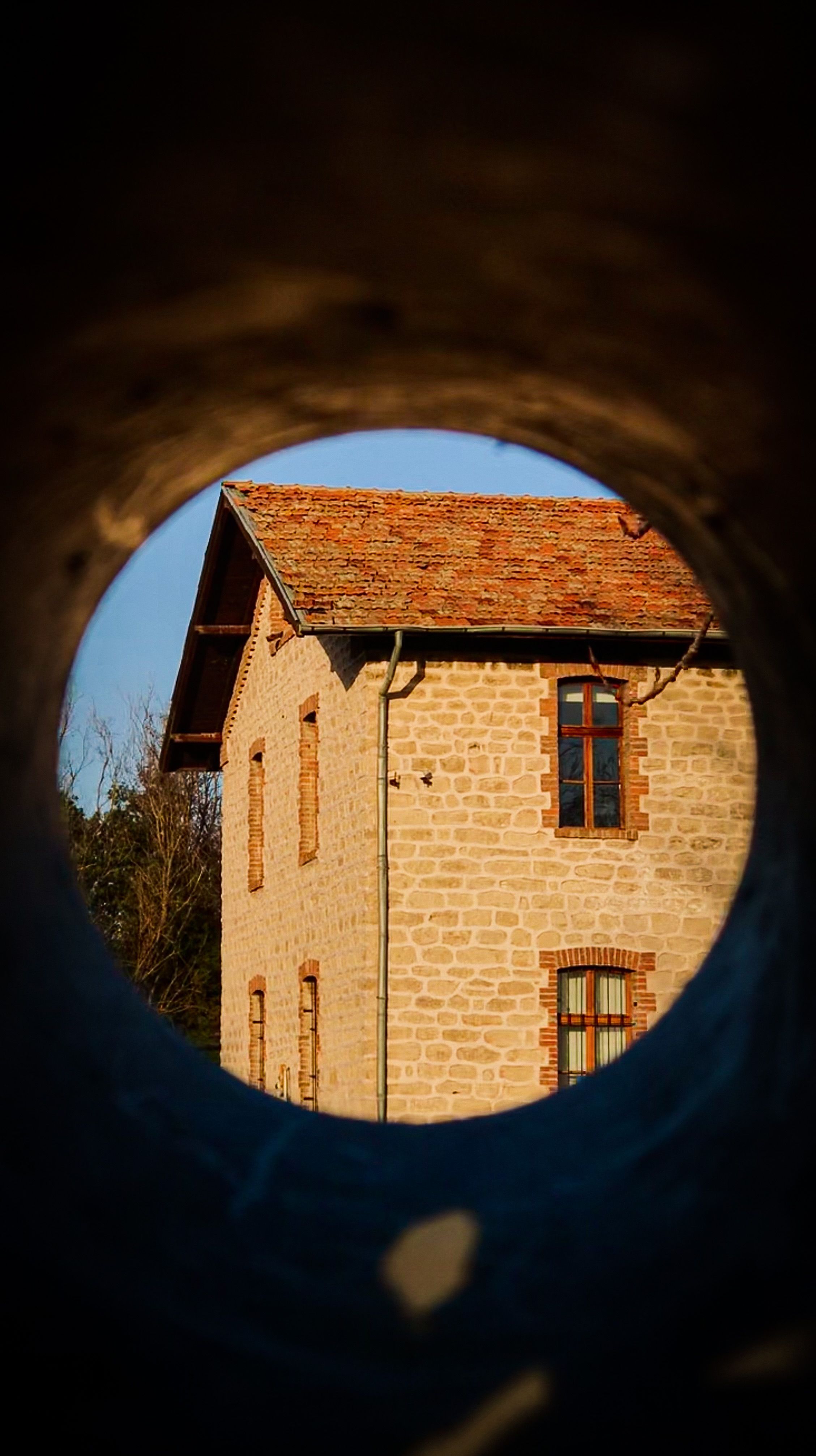 View of a Brick Building through a Circular Hole · Free Stock Photo