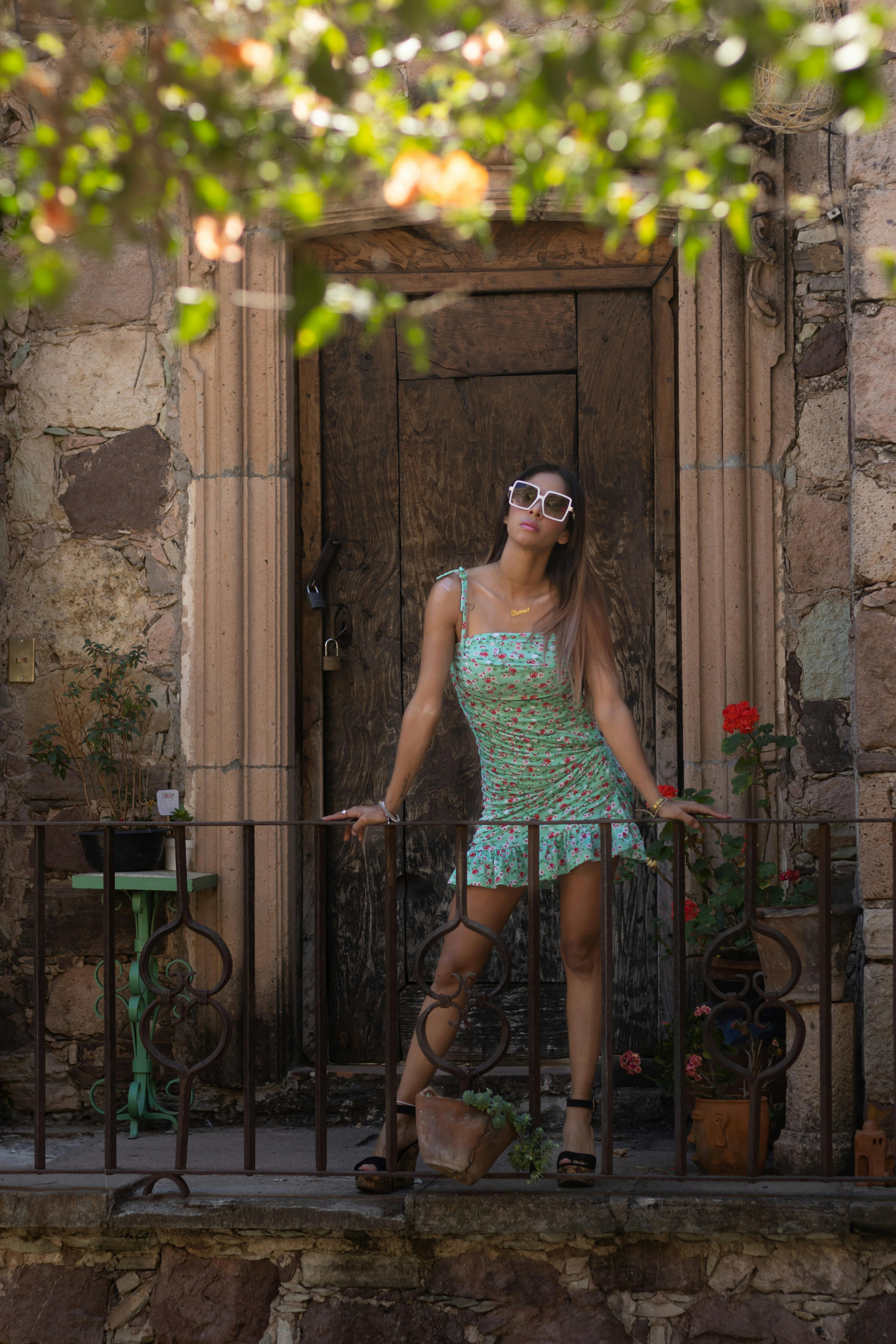 Woman in a Sundress and Sunglasses Posing by a Railing · Free Stock Photo