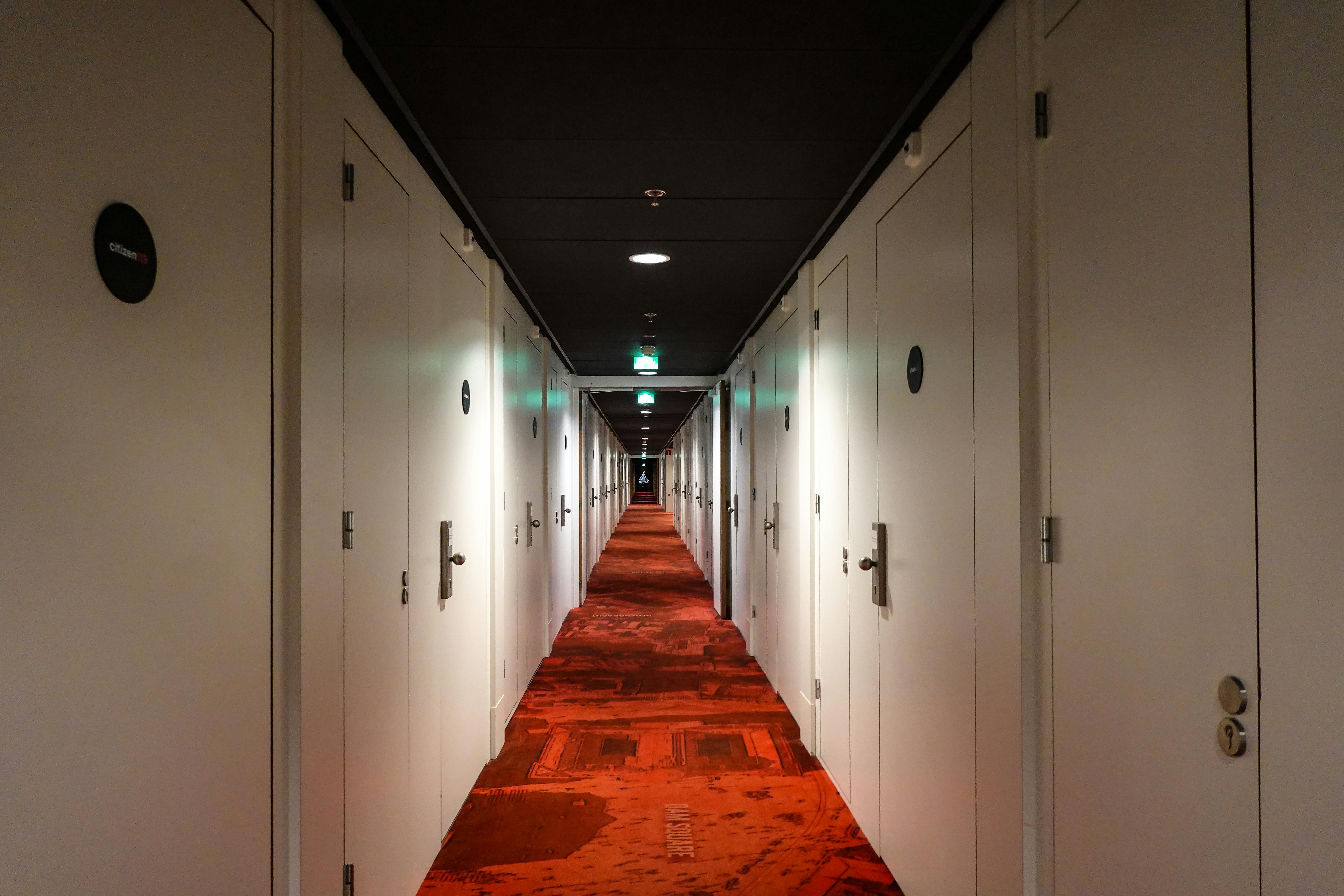 Symmetrical View of a Narrow Hotel Corridor · Free Stock Photo