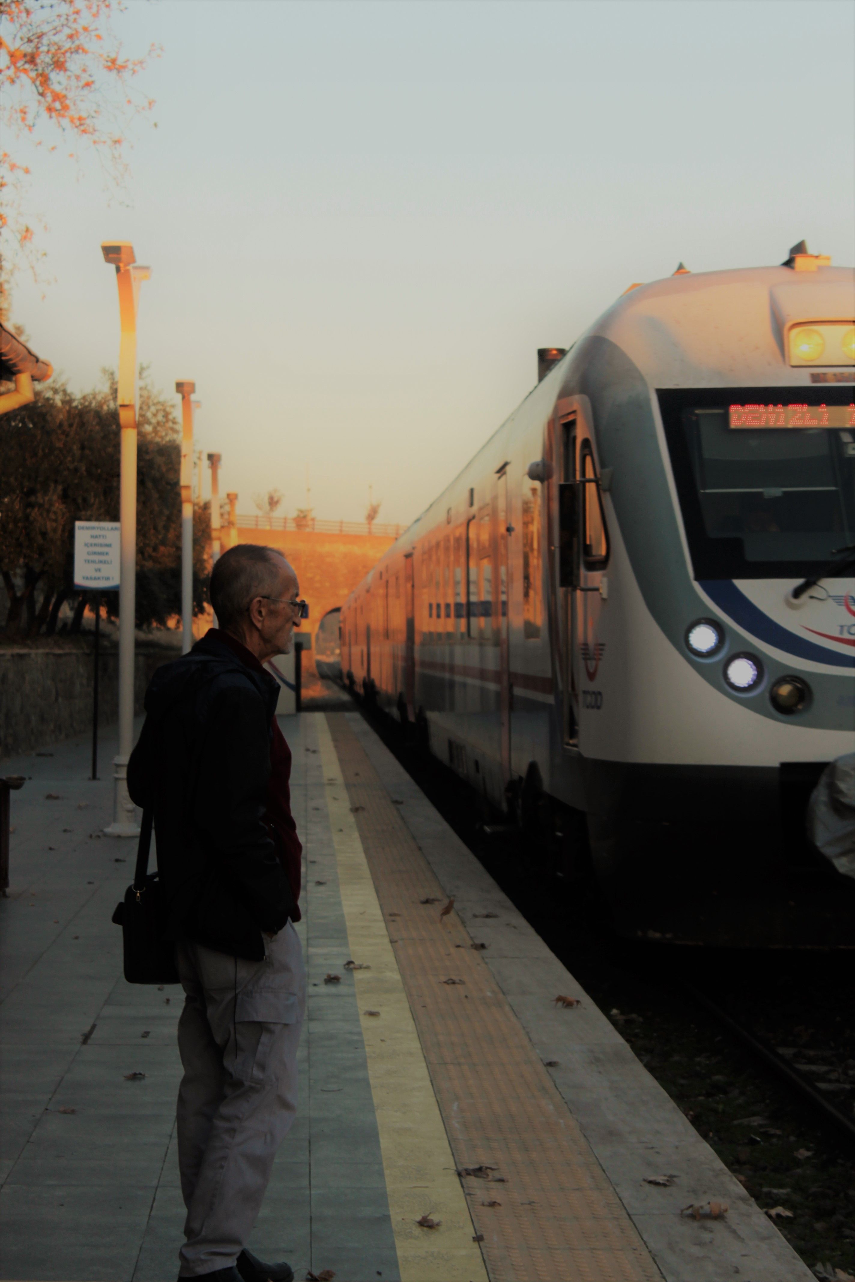 Man Standing on a Platform with a Train Approaching the Station · Free ...