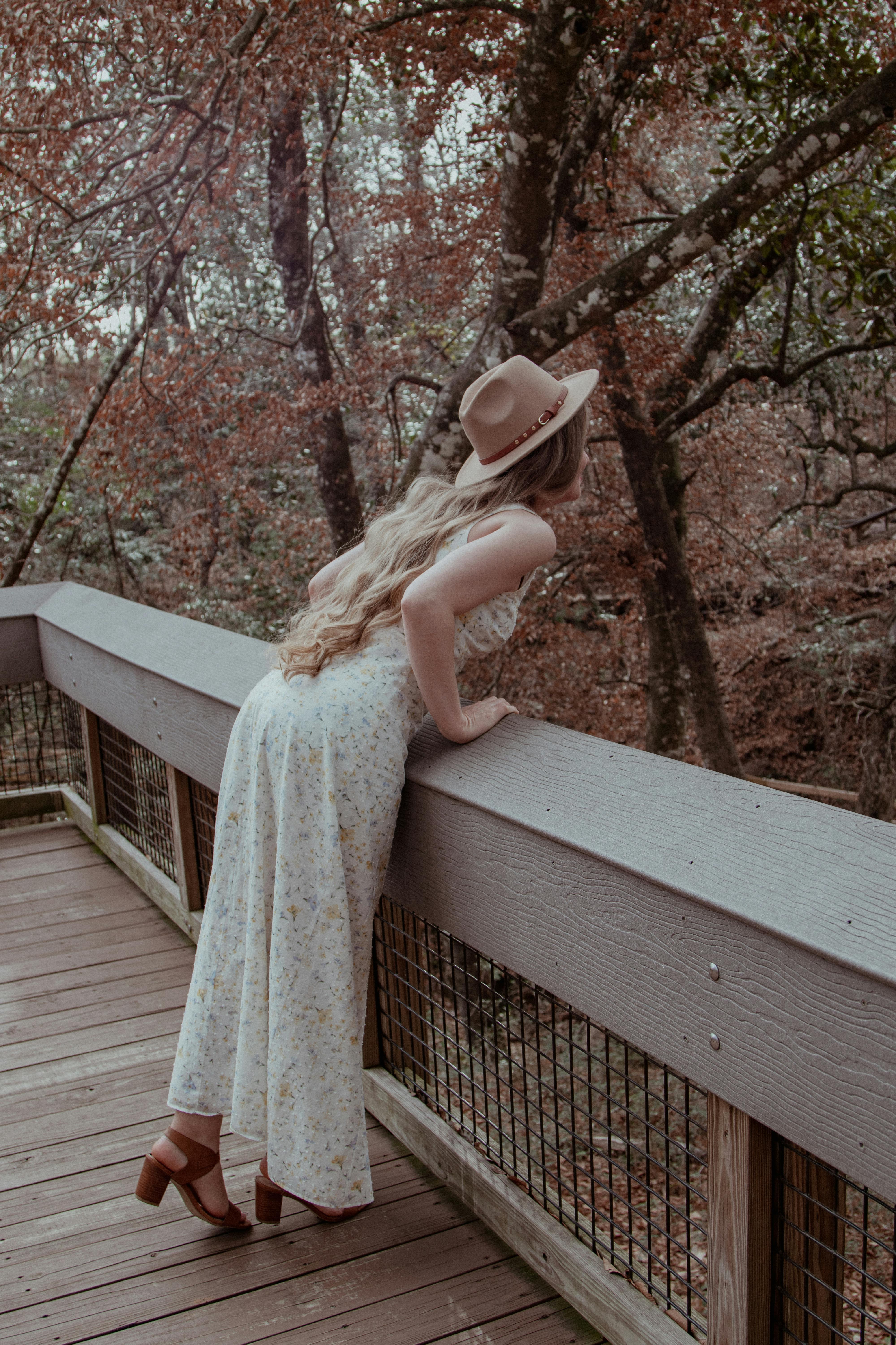 Woman in a Long Sundress and a Hat Leaning Over the Terrace Railing ...
