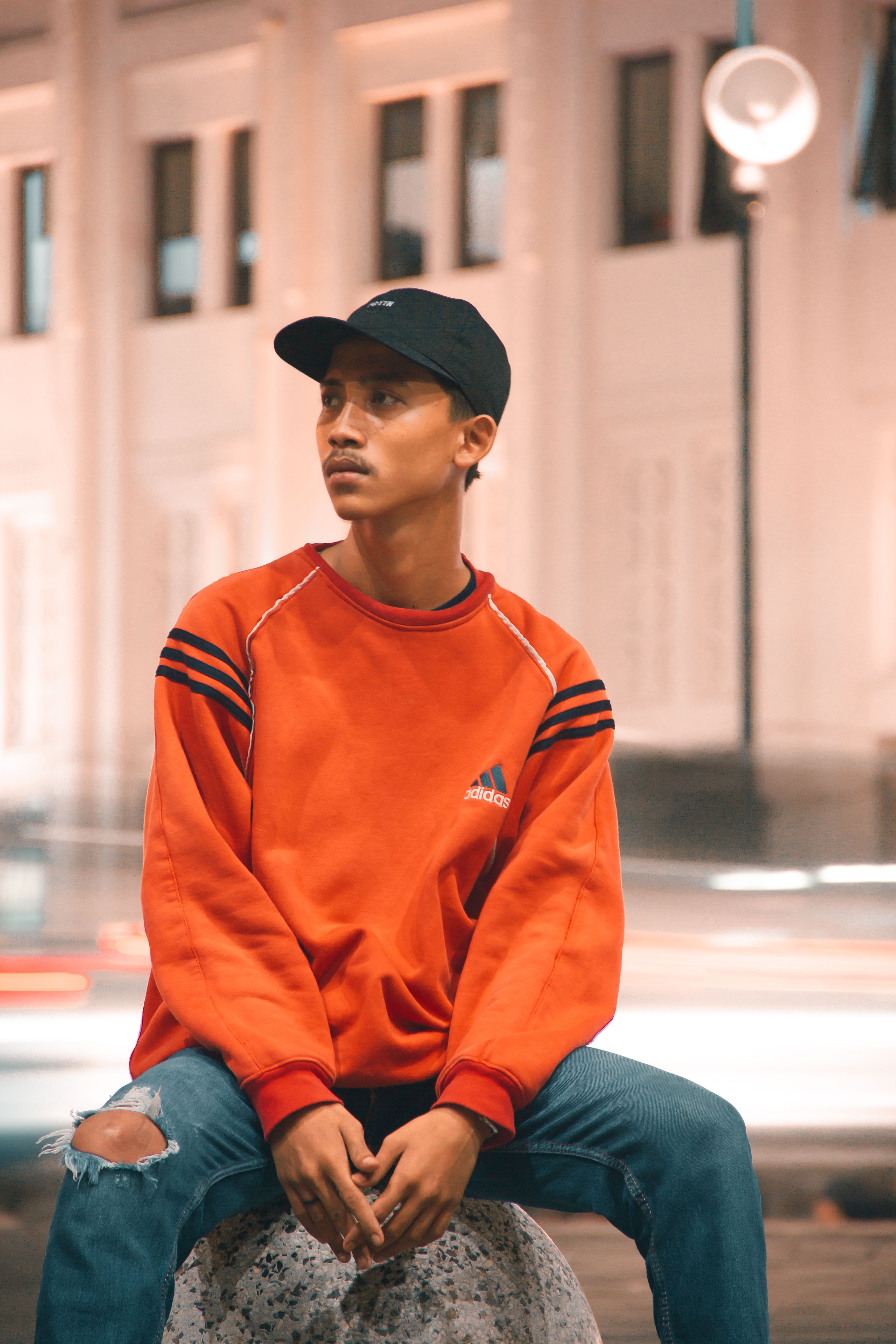 Man in Sweatshirt Sitting on Street · Free Stock Photo