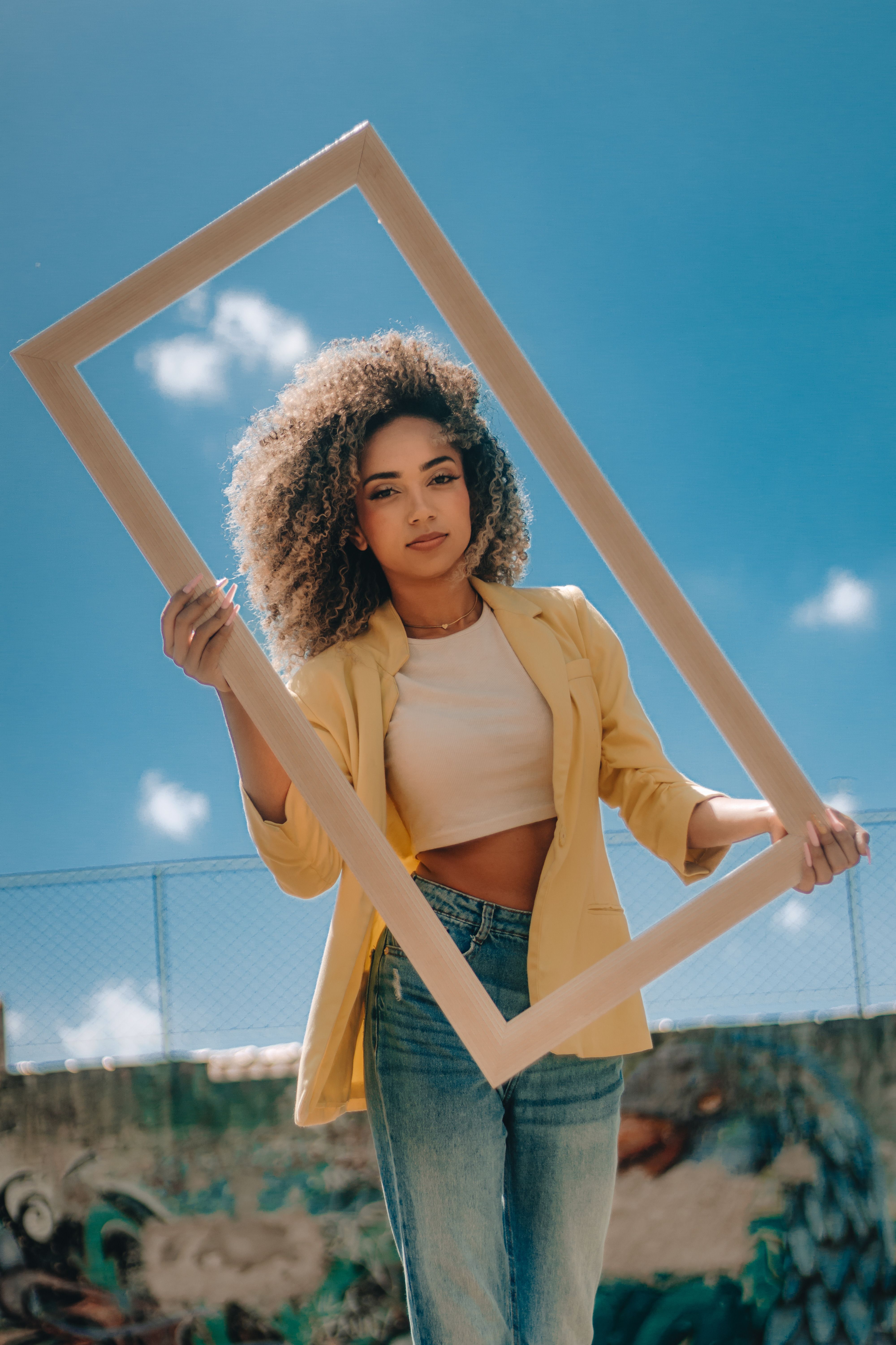 Beautiful Woman Standing and Holding a Frame against Blue Sky · Free ...