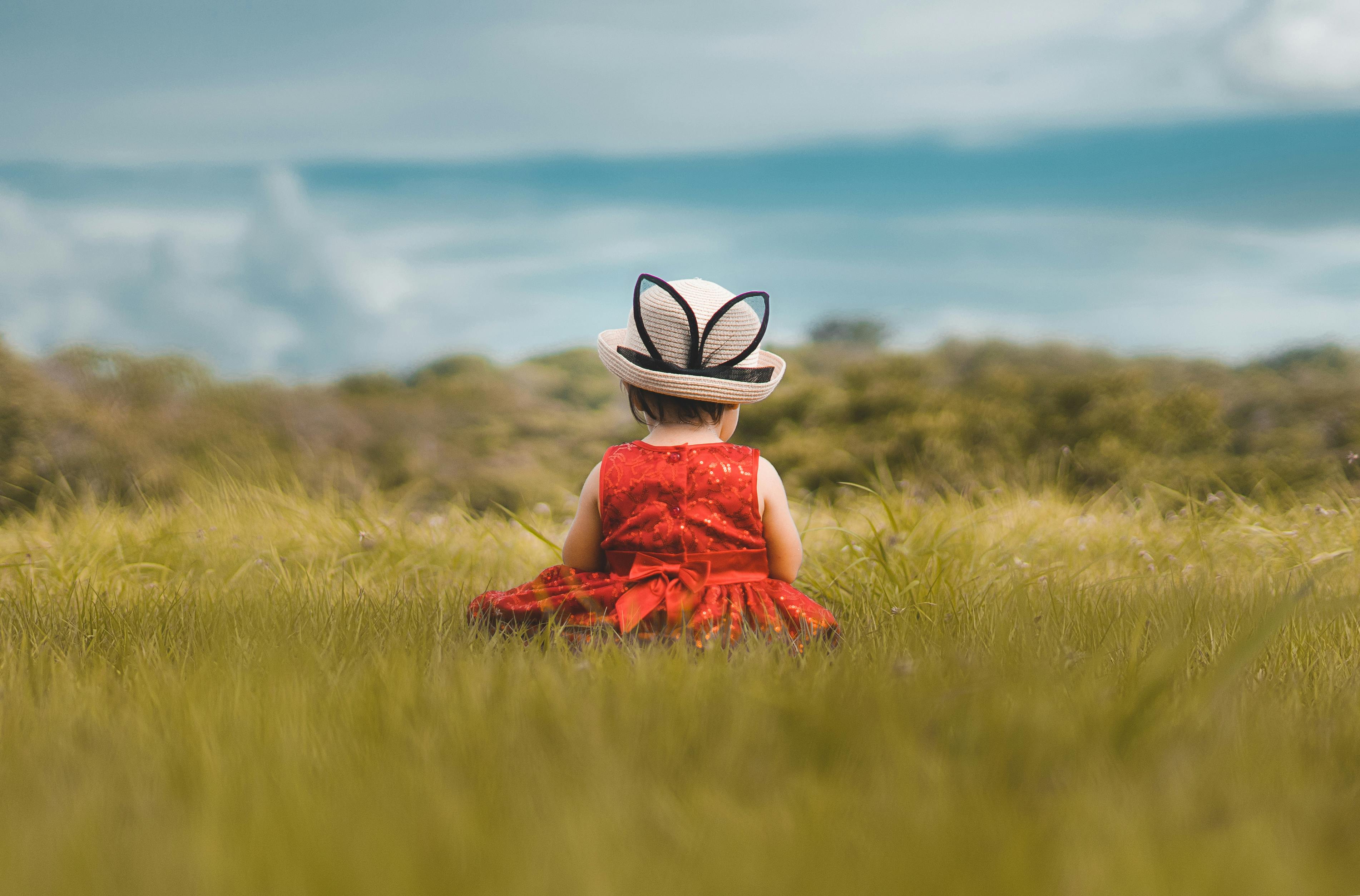 Girl Sitting on Grass Field Holding Pampas Grass · Free Stock Photo