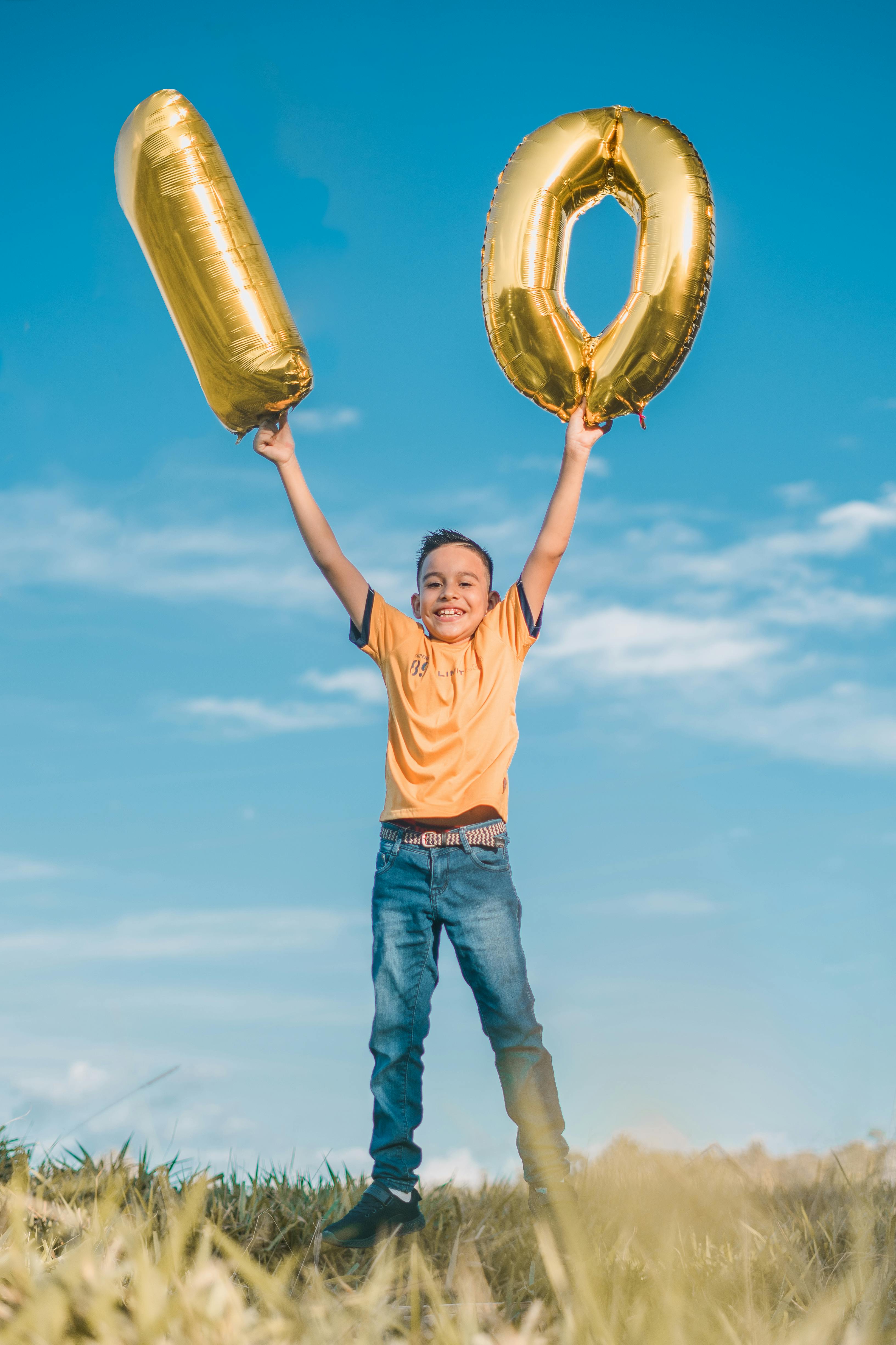 A Boy Standing on a Meadow and Holding Up Balloons with Number 10 ...