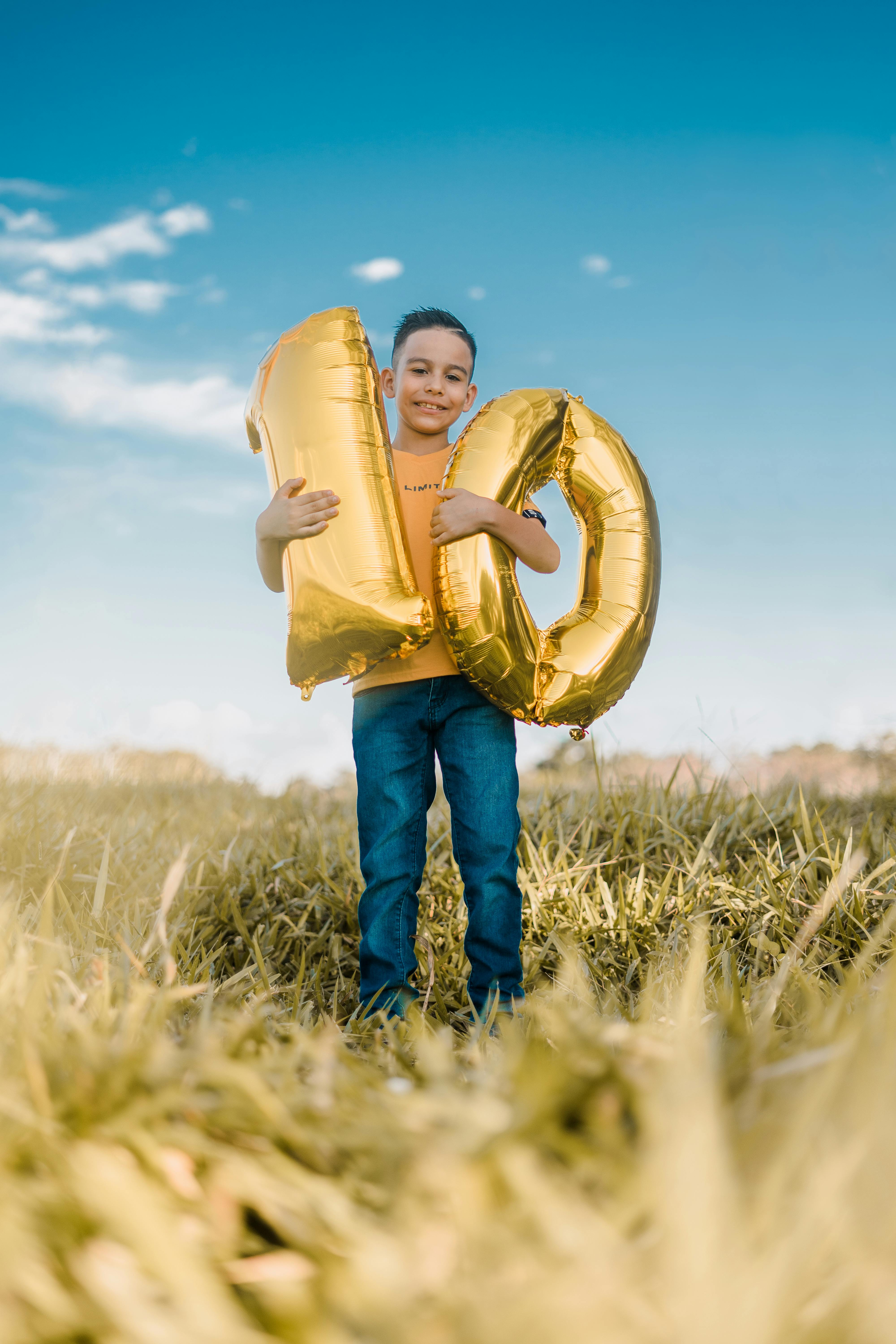 Boy Holding Birthday Balloons in Countryside · Free Stock Photo