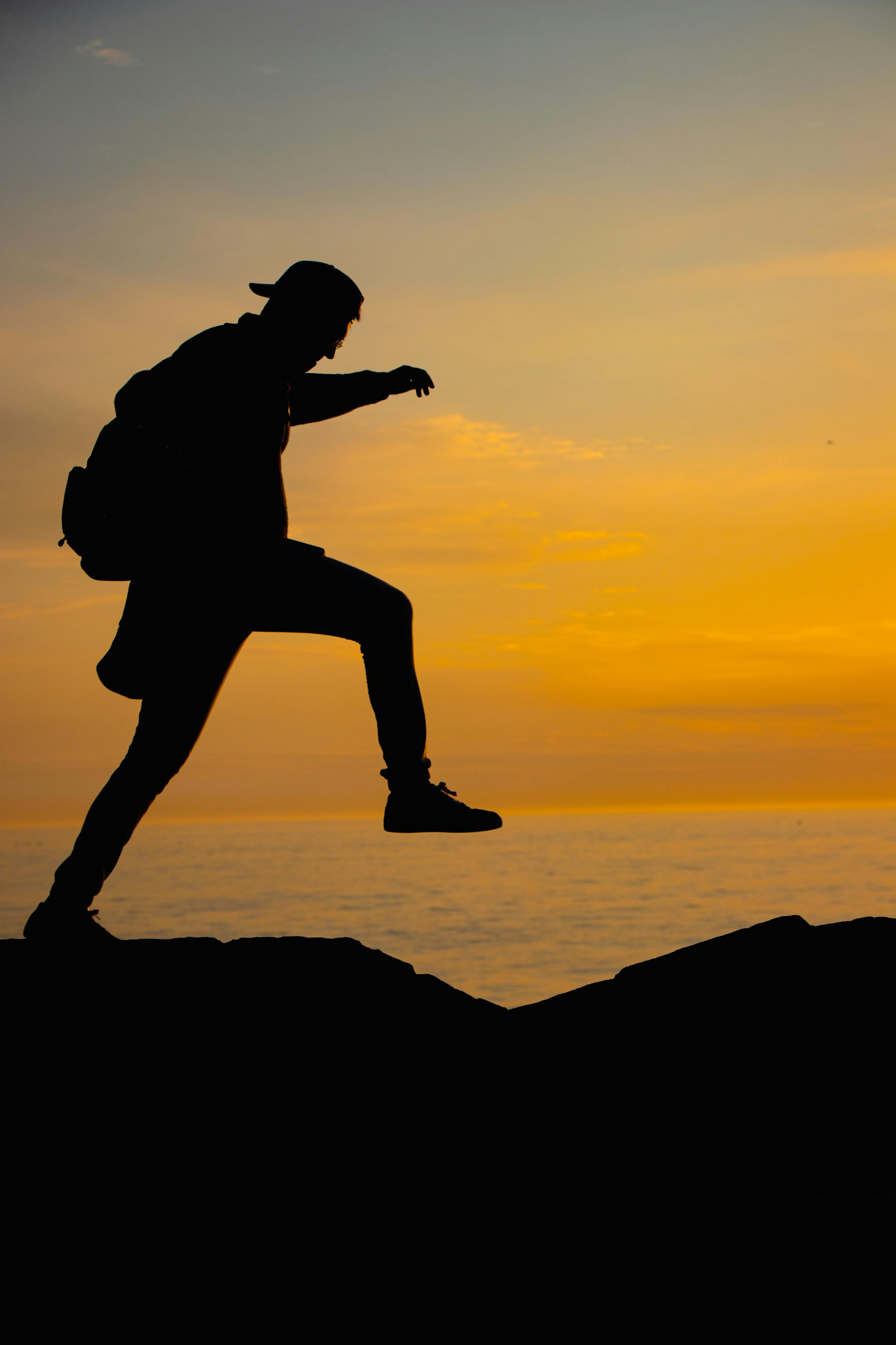 Silhouette of Man Jumping on Rocks on Sunset · Free Stock Photo