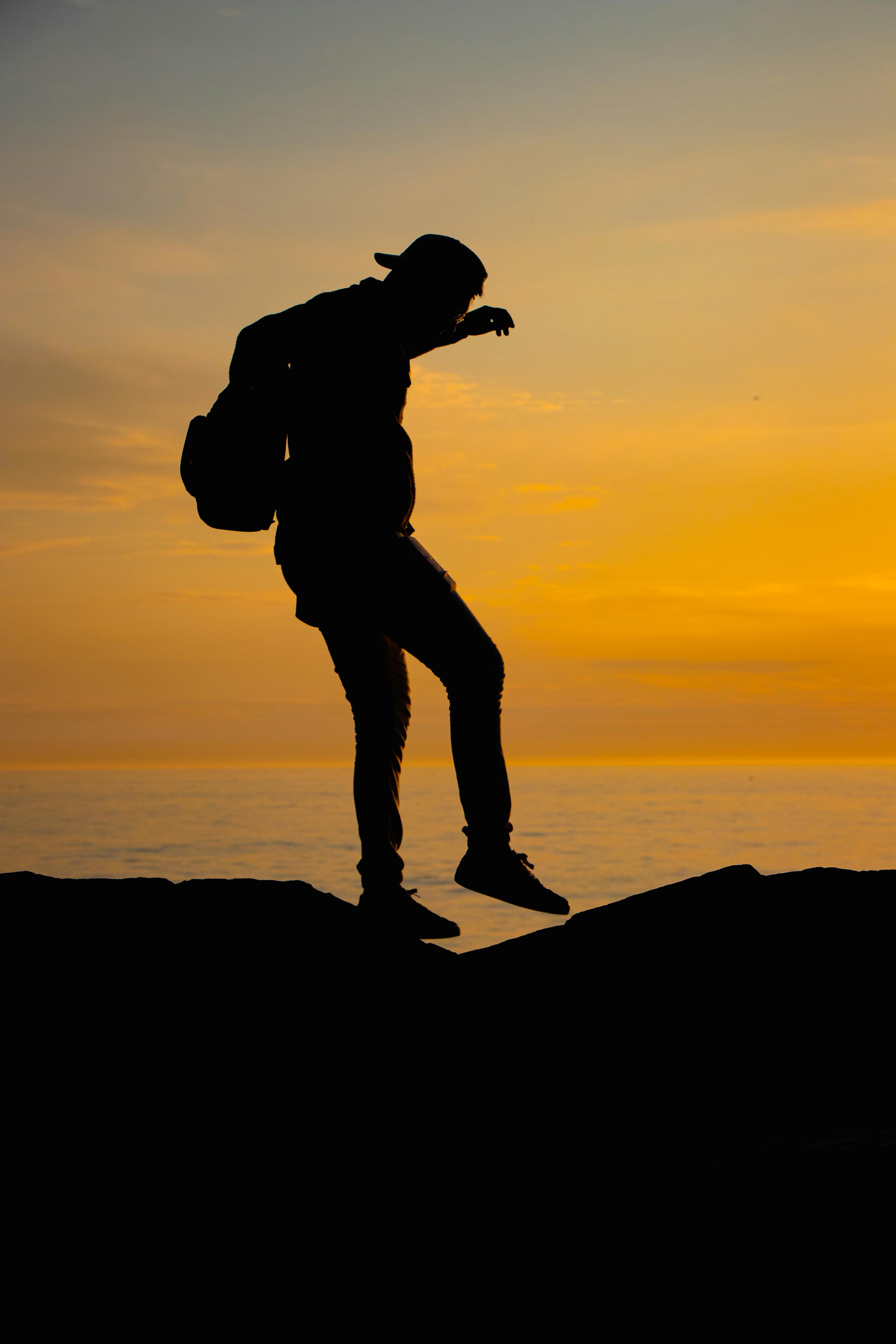 Silhouette of Man Jumping on Rocks on Sunset · Free Stock Photo