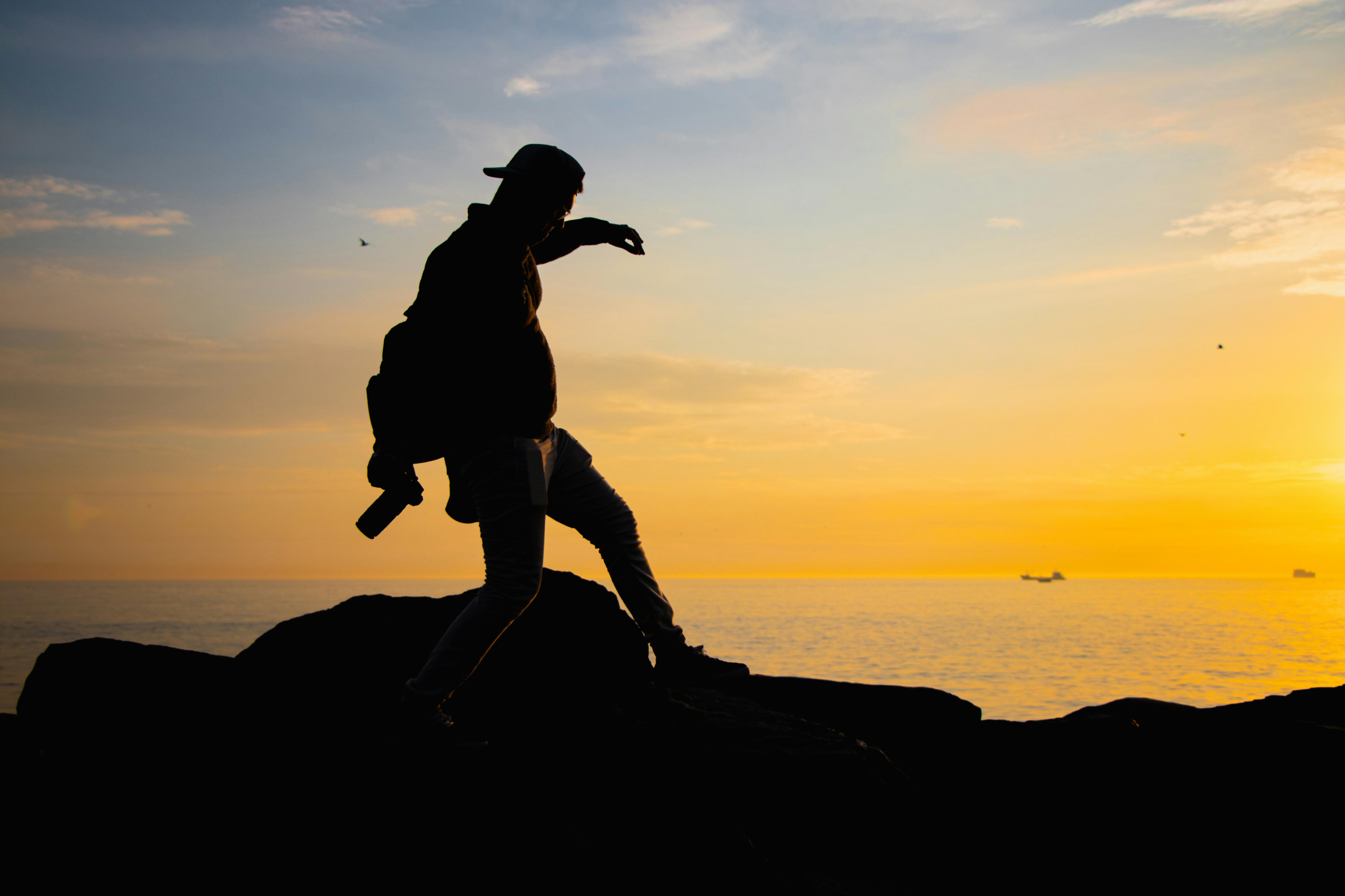 Silhouette of Man Jumping on Rocks on Sunset · Free Stock Photo