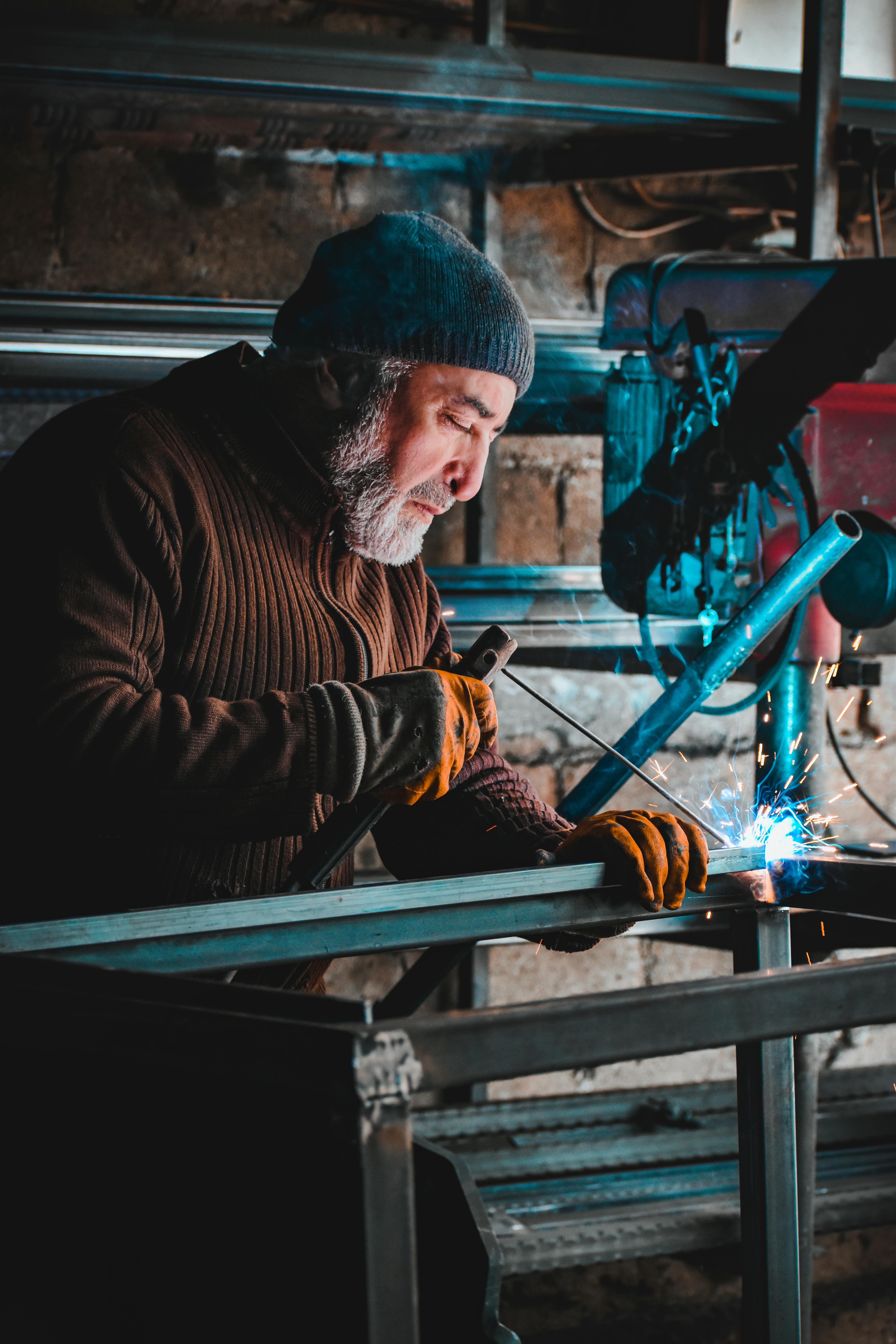 Old Bearded Man Welding Metal in Dark · Free Stock Photo