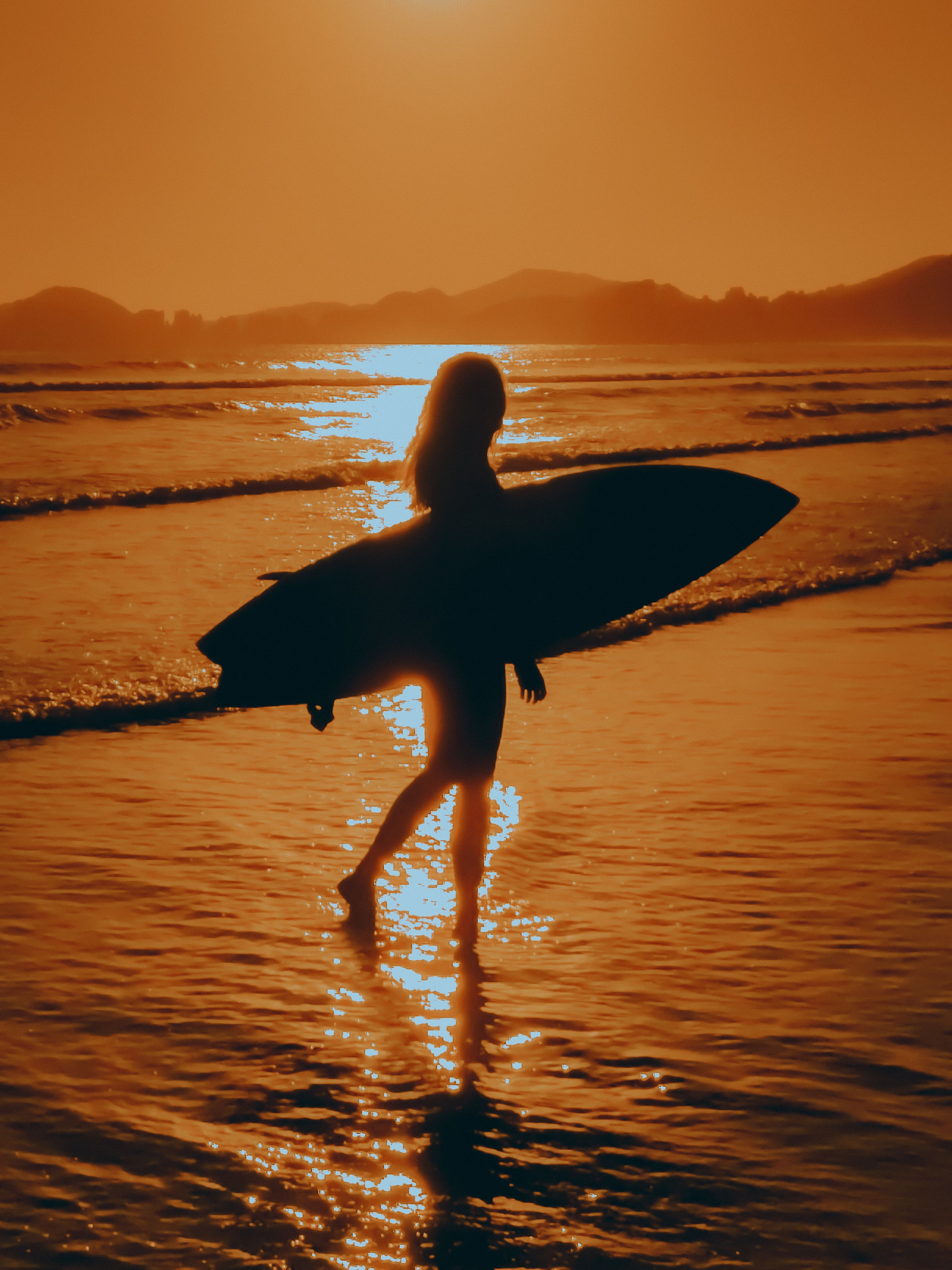 Woman Carrying Surfboard at Sunset · Free Stock Photo