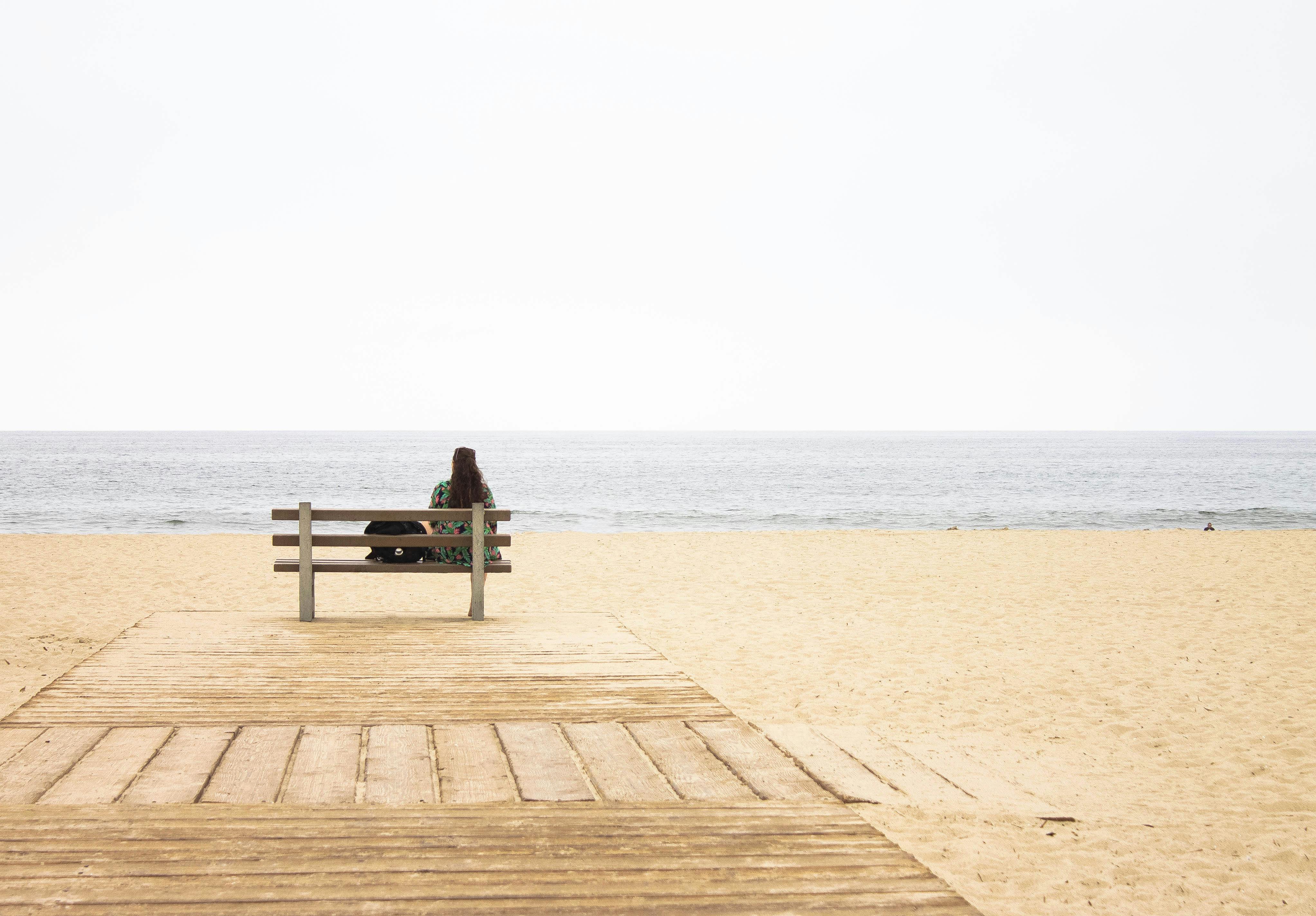A Person Sitting on a Bench on a Beach · Free Stock Photo
