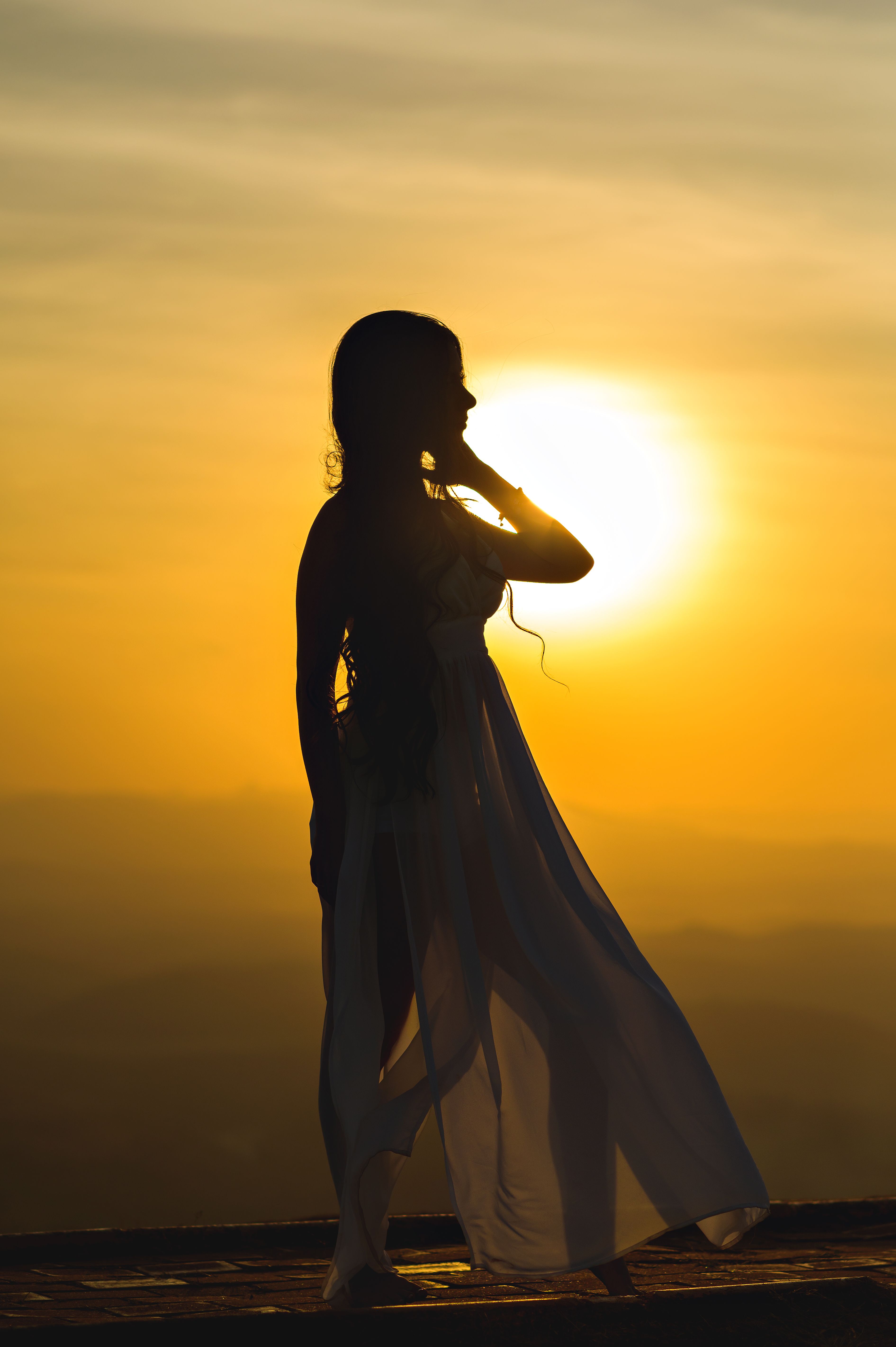 Silhouette of a Woman in a Dress Standing Outdoors at Sunset · Free ...