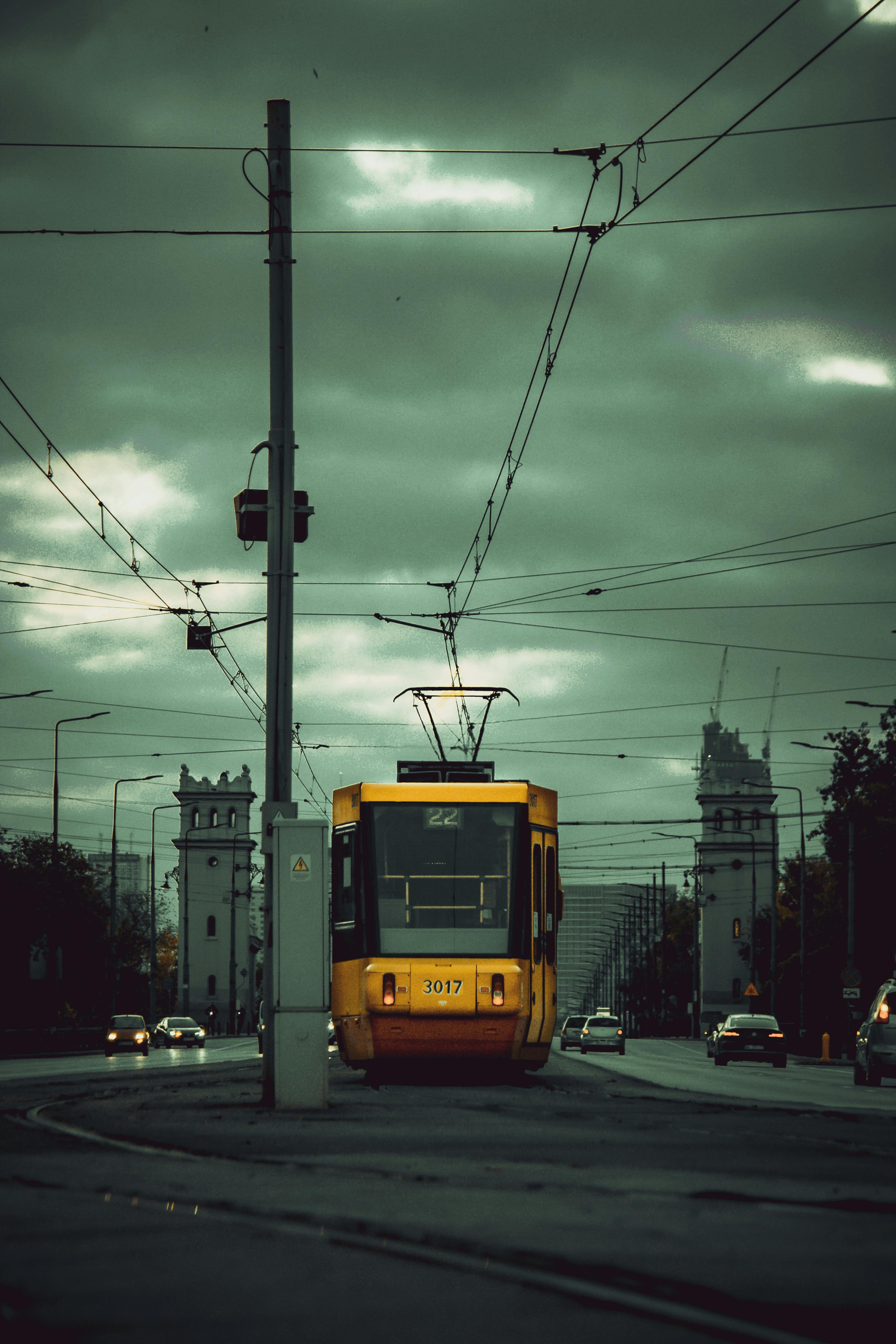 A yellow trolley on a street with power lines · Free Stock Photo