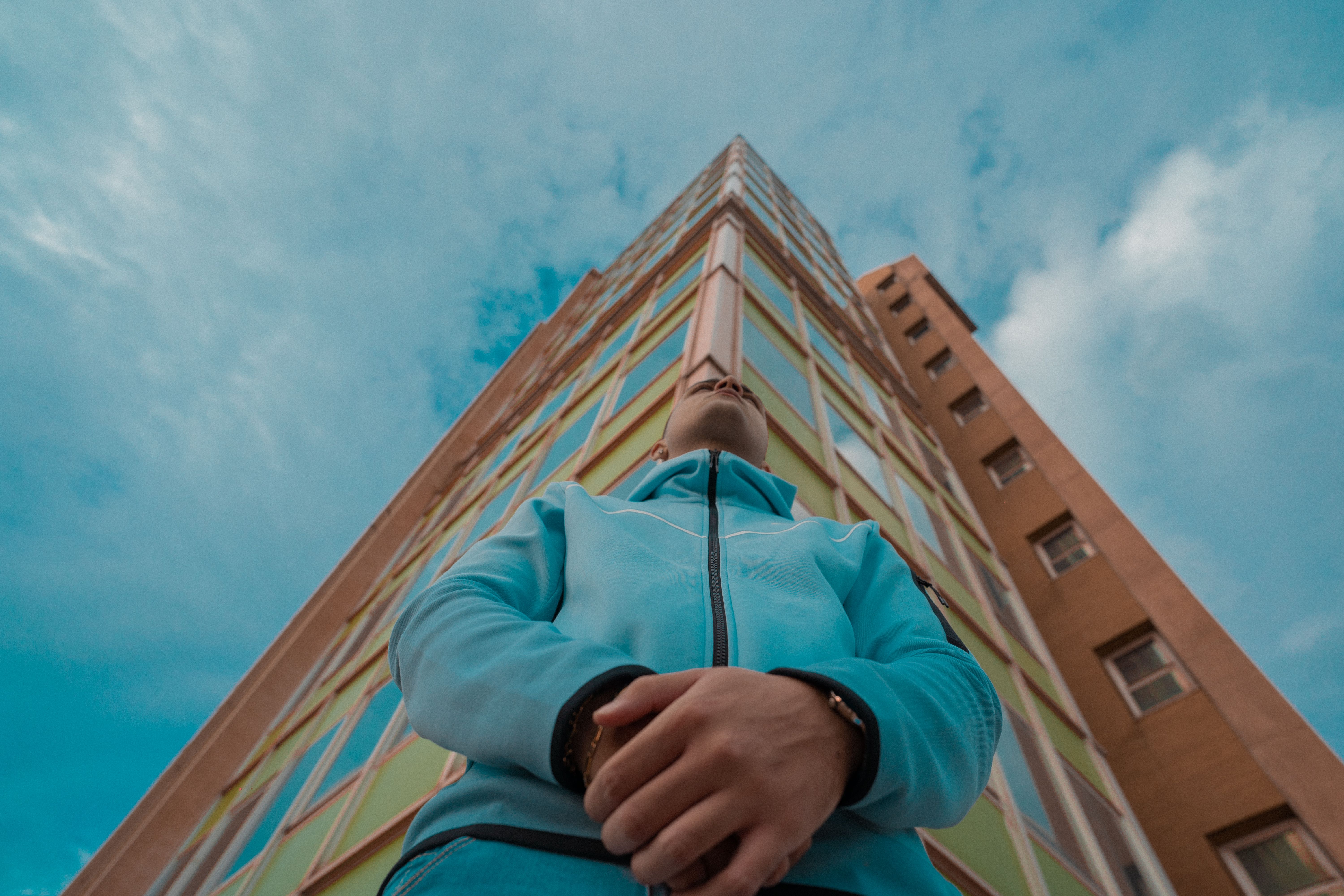 Low Angle Shot of a Young Man Standing on the Background of a Block of ...
