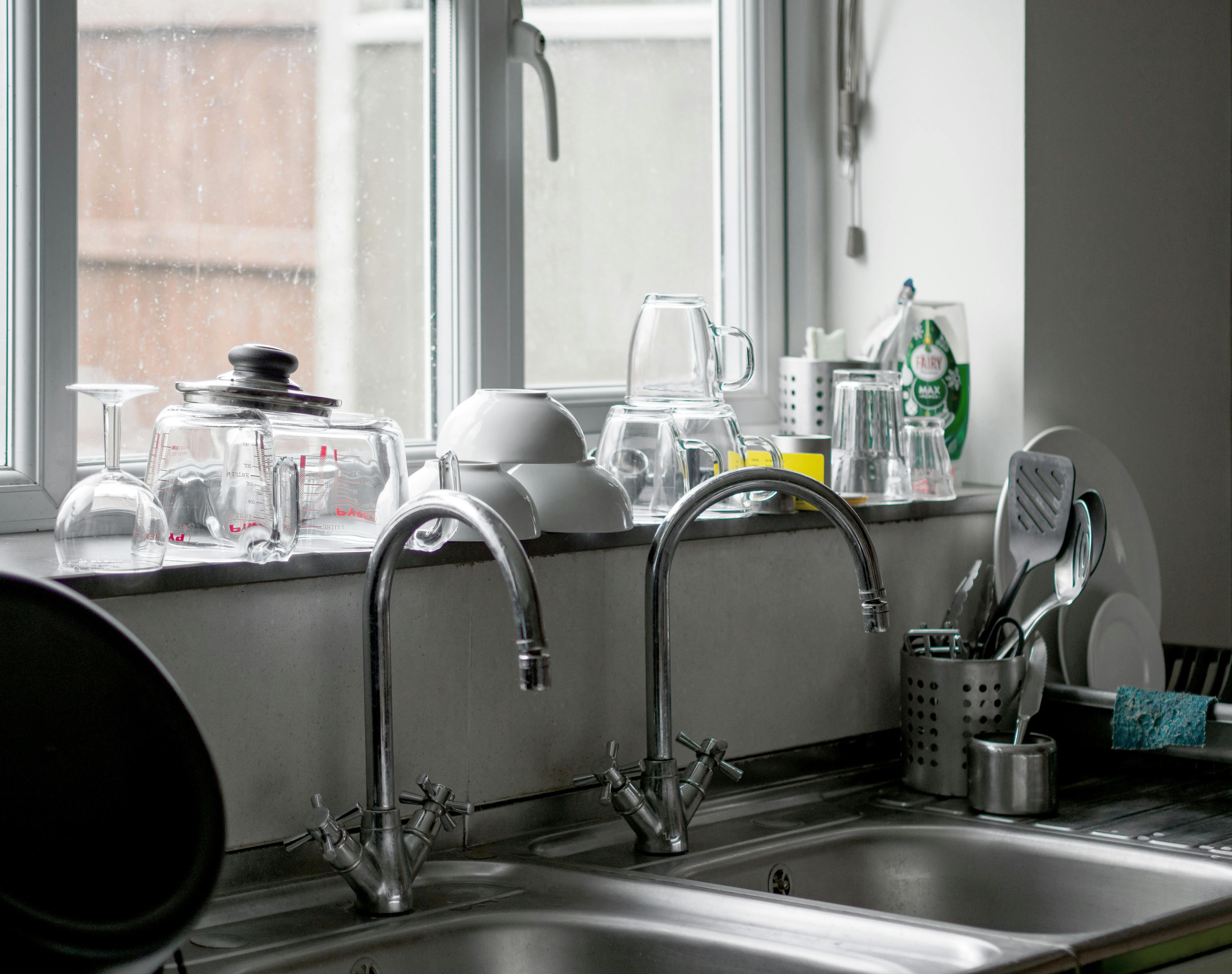 View of Two Sinks near a Window with Bowls and Glassware on the ...