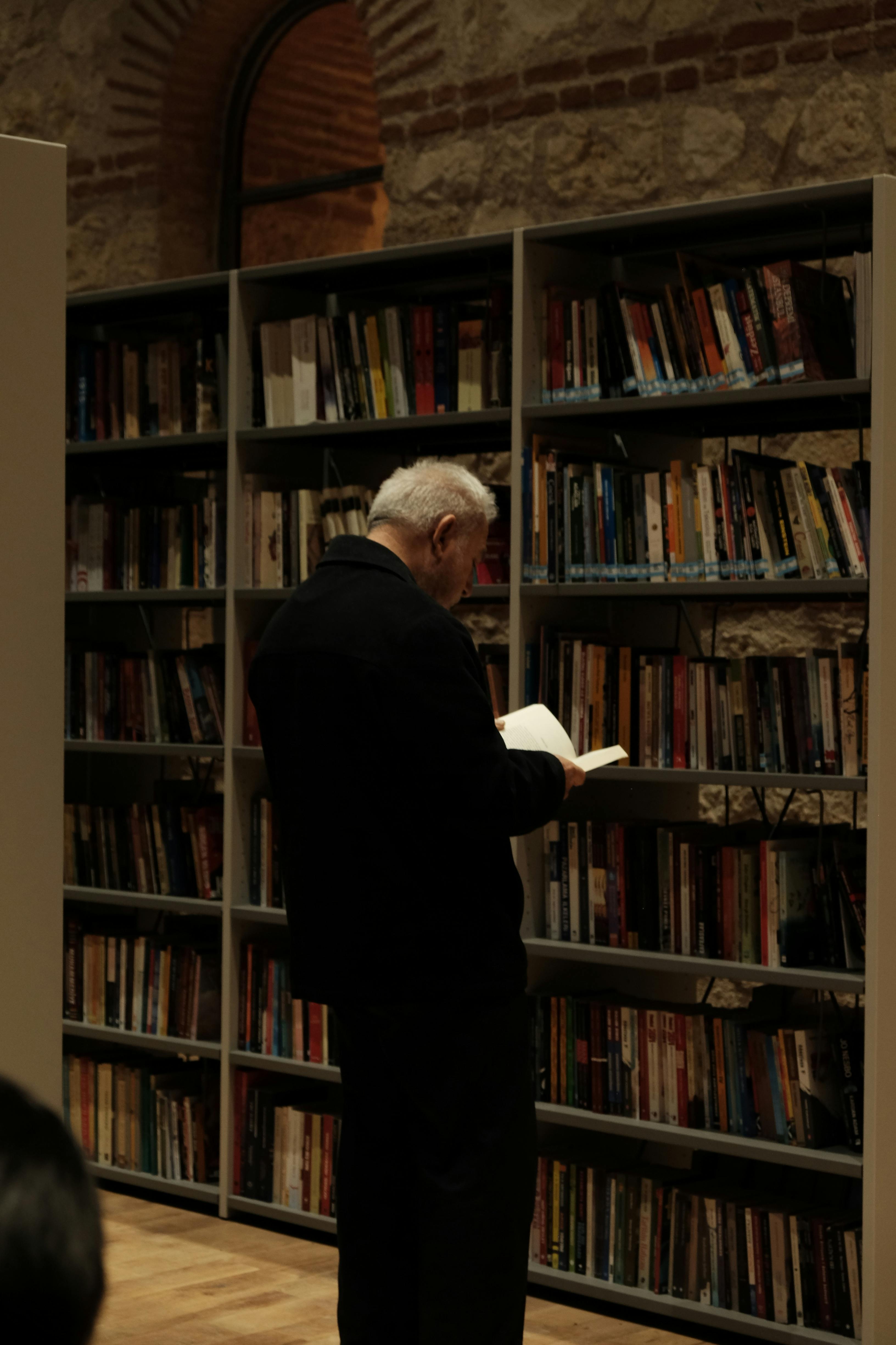 Man Standing and Reading in Library · Free Stock Photo