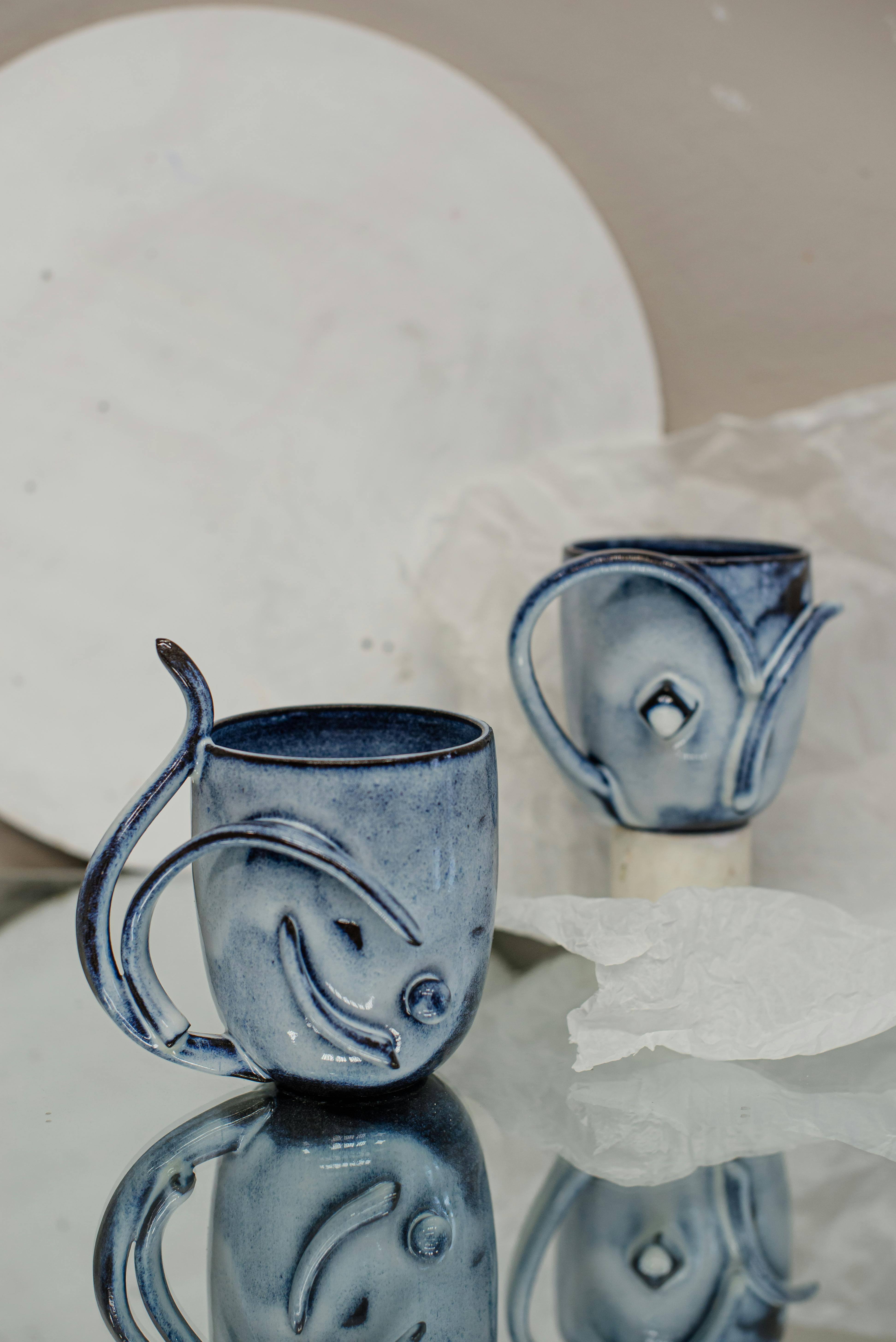 Two blue cups with handles and a mirror on a table · Free Stock Photo