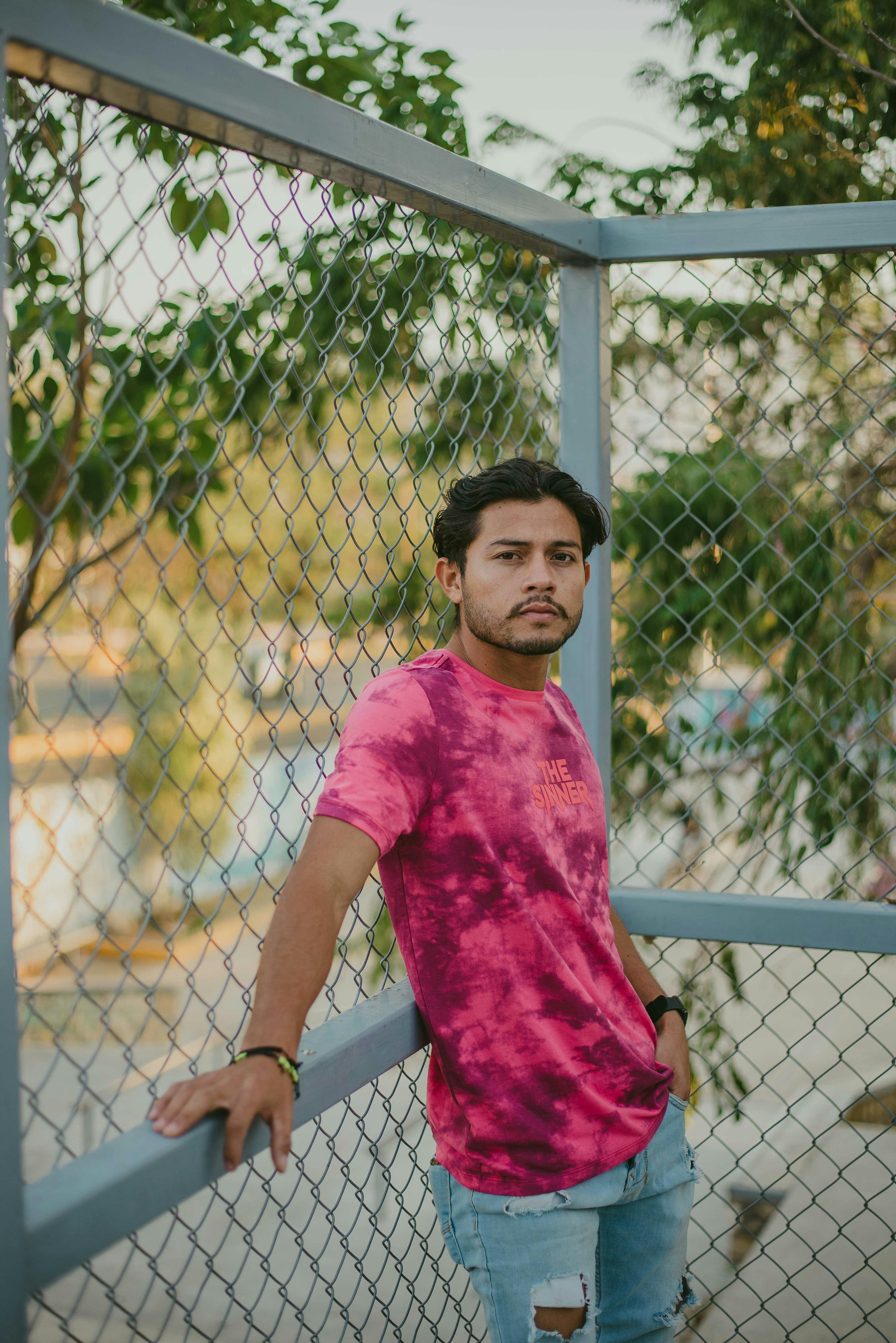 Man Sitting and Leaning on the Metal Fence · Free Stock Photo