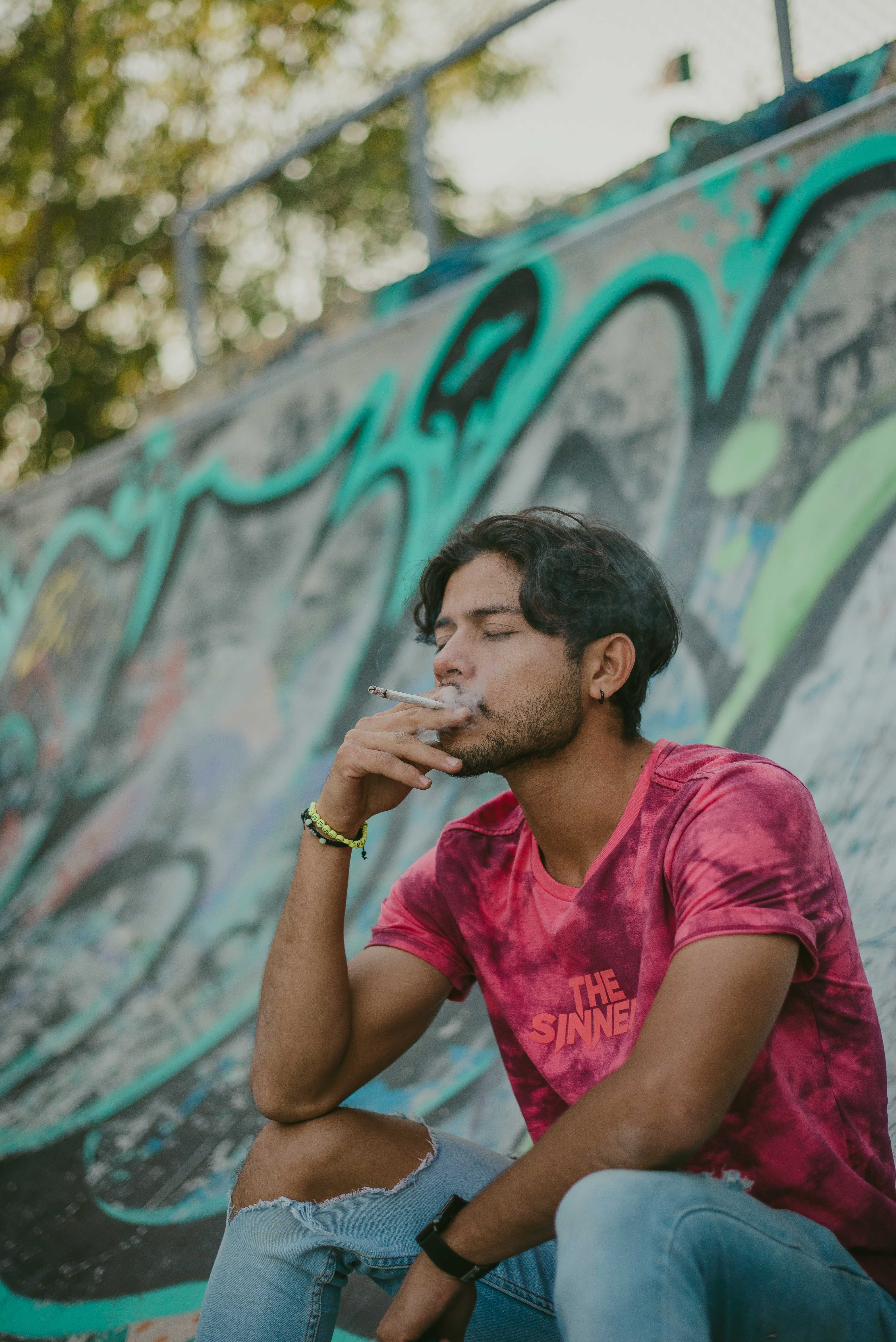 A Man Sitting Outside and Smoking a Cigarette · Free Stock Photo