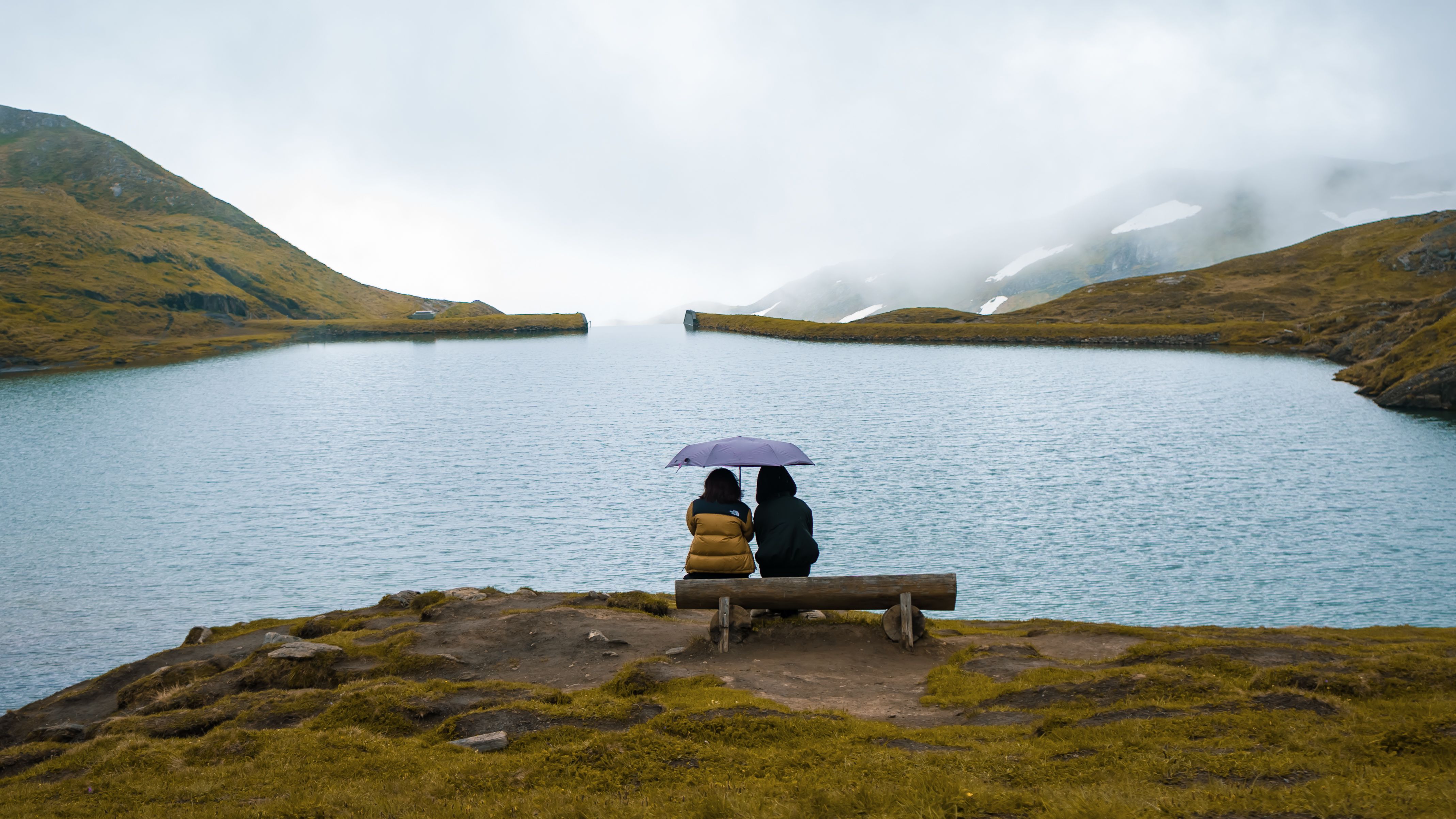 Woman with Umbrella Sitting on Bench with Coaches behind · Free Stock Photo