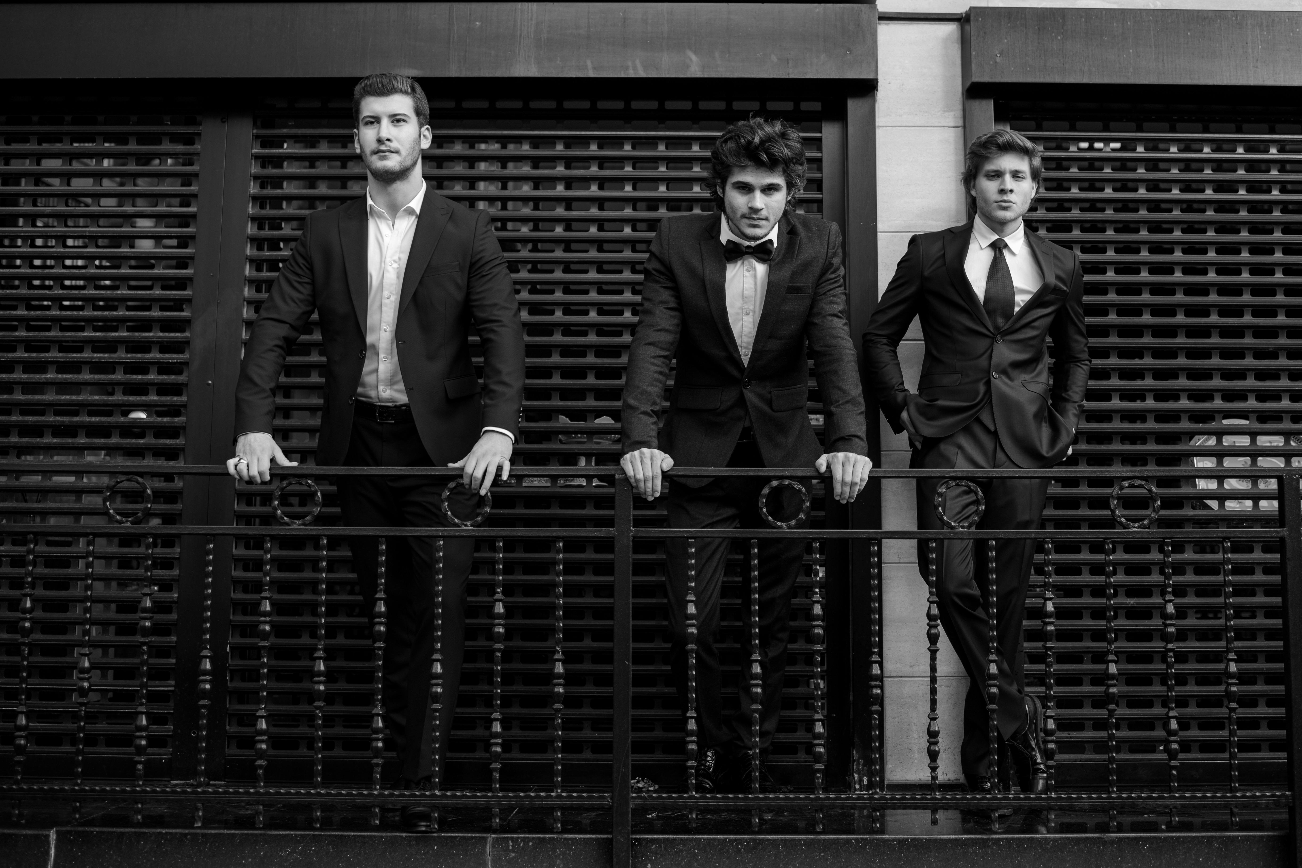 Three Men in Suits Leaning on a Balustrade on a Terrace · Free Stock Photo