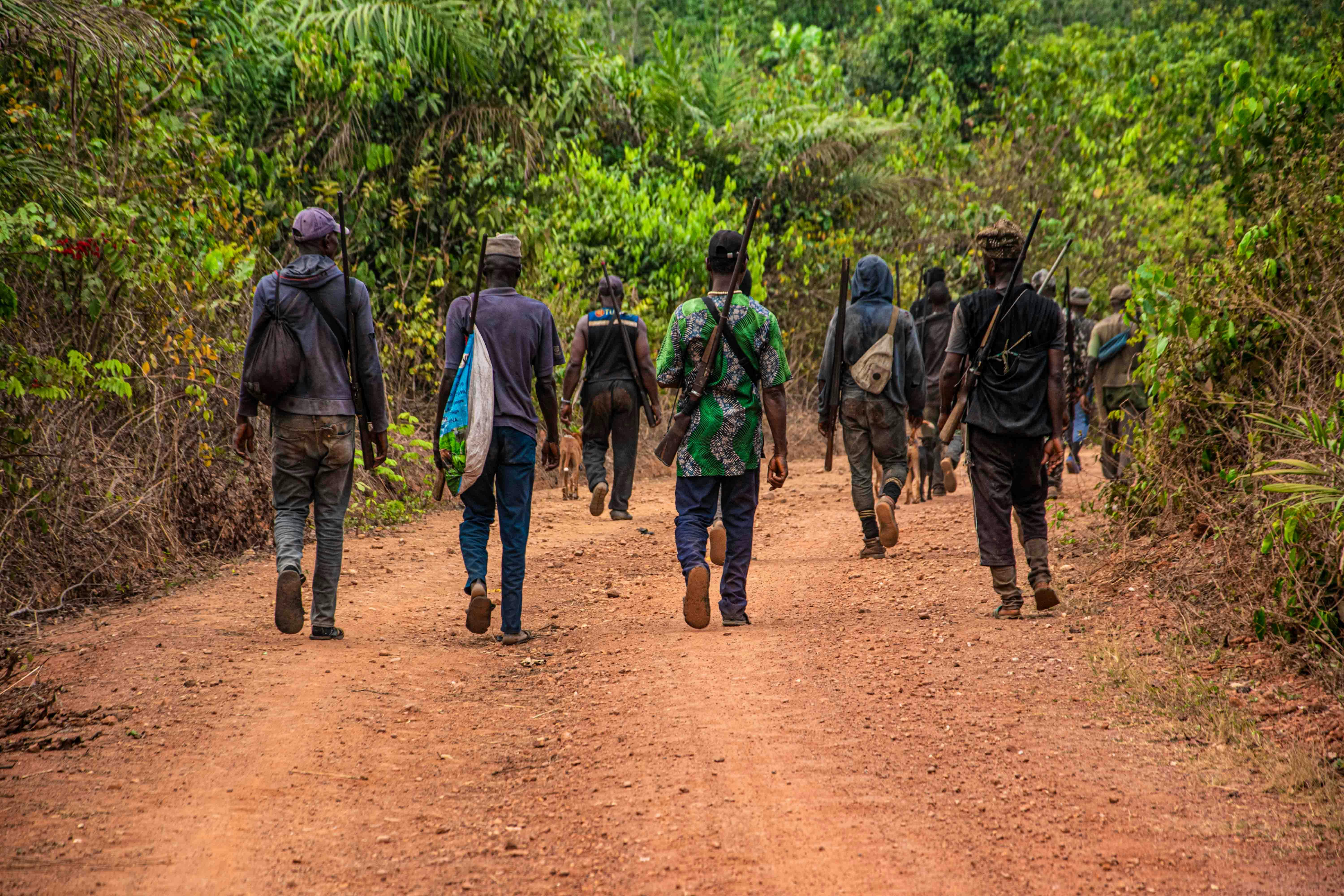 People Carrying Rifle while Walking on the Dirt Road · Free Stock Photo