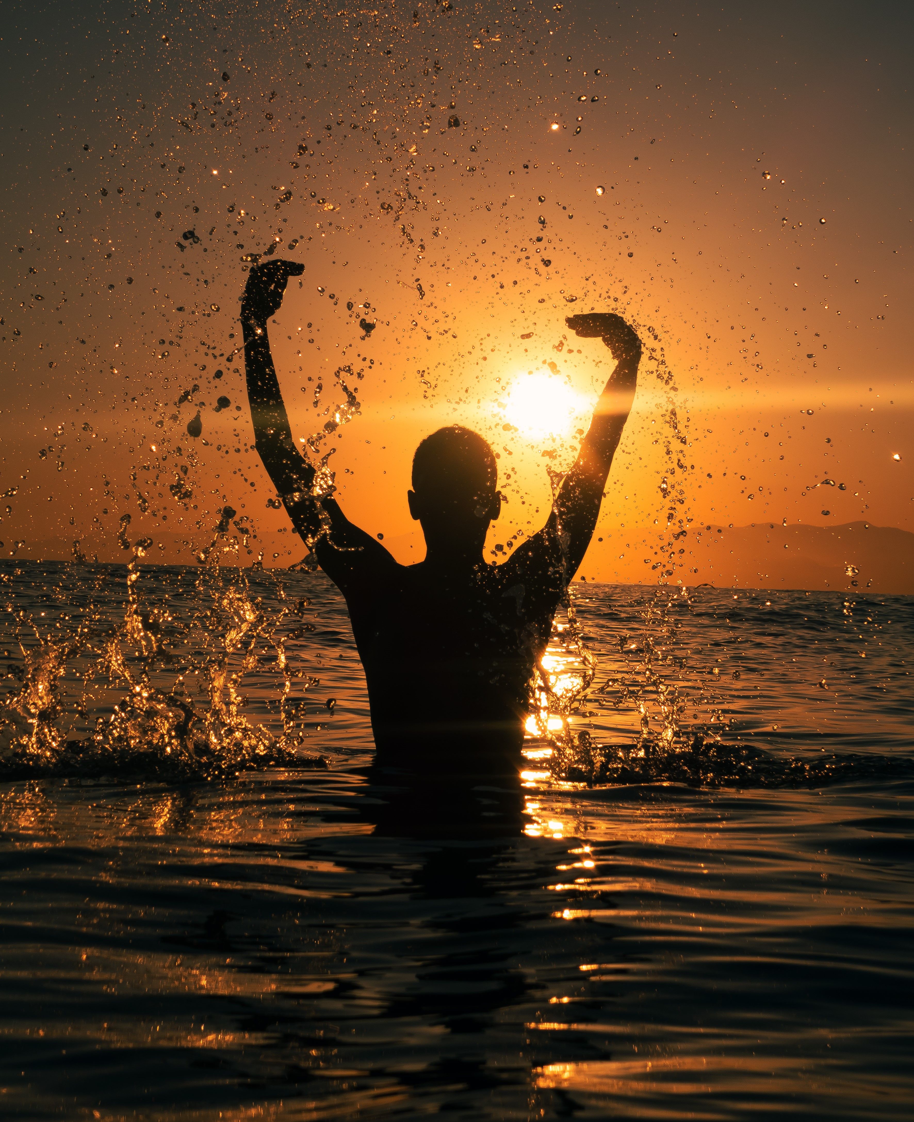 Silhouette of a Man Standing in the Sea Splashing Water Under the ...