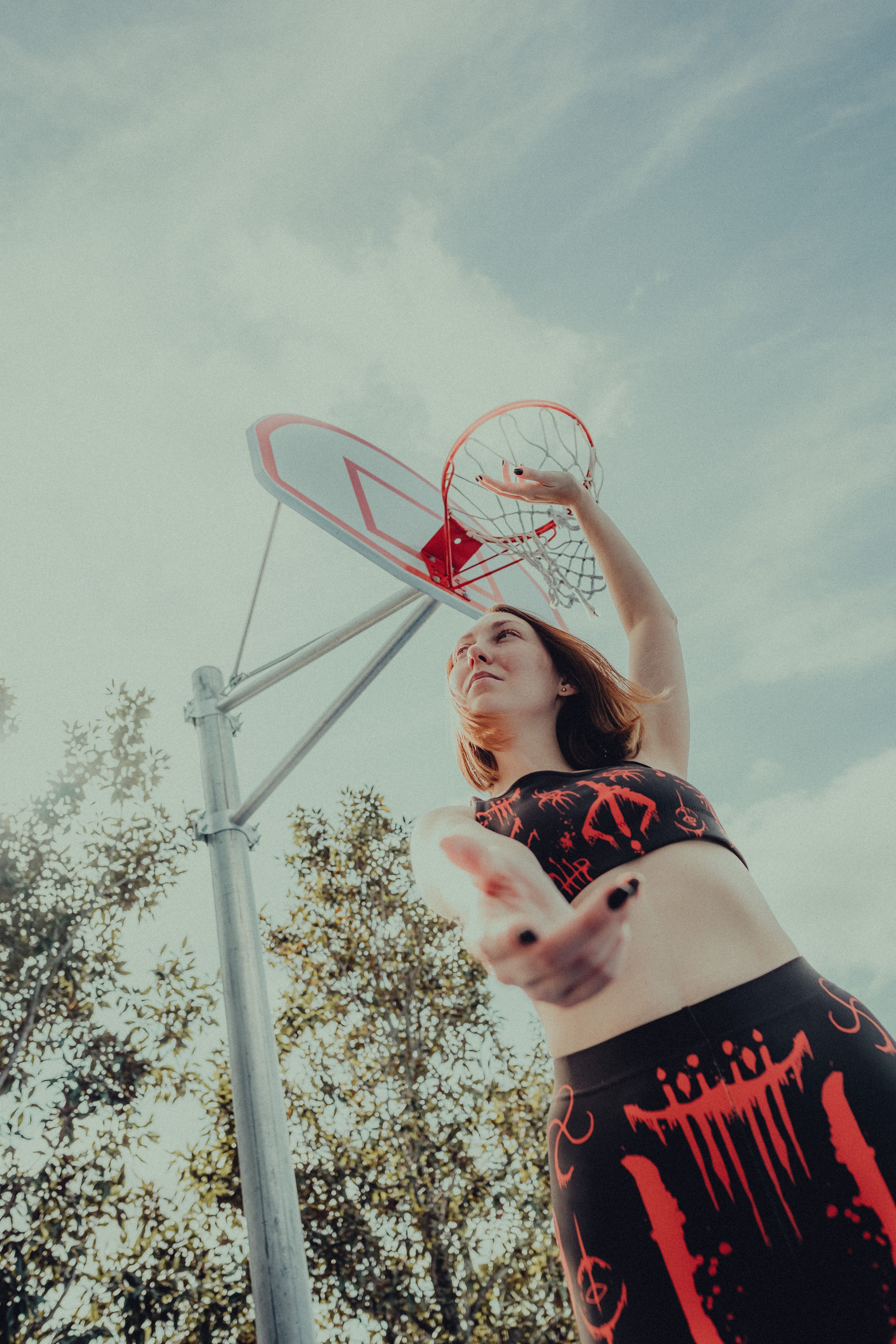 Woman Standing under a Basketball Hoop · Free Stock Photo