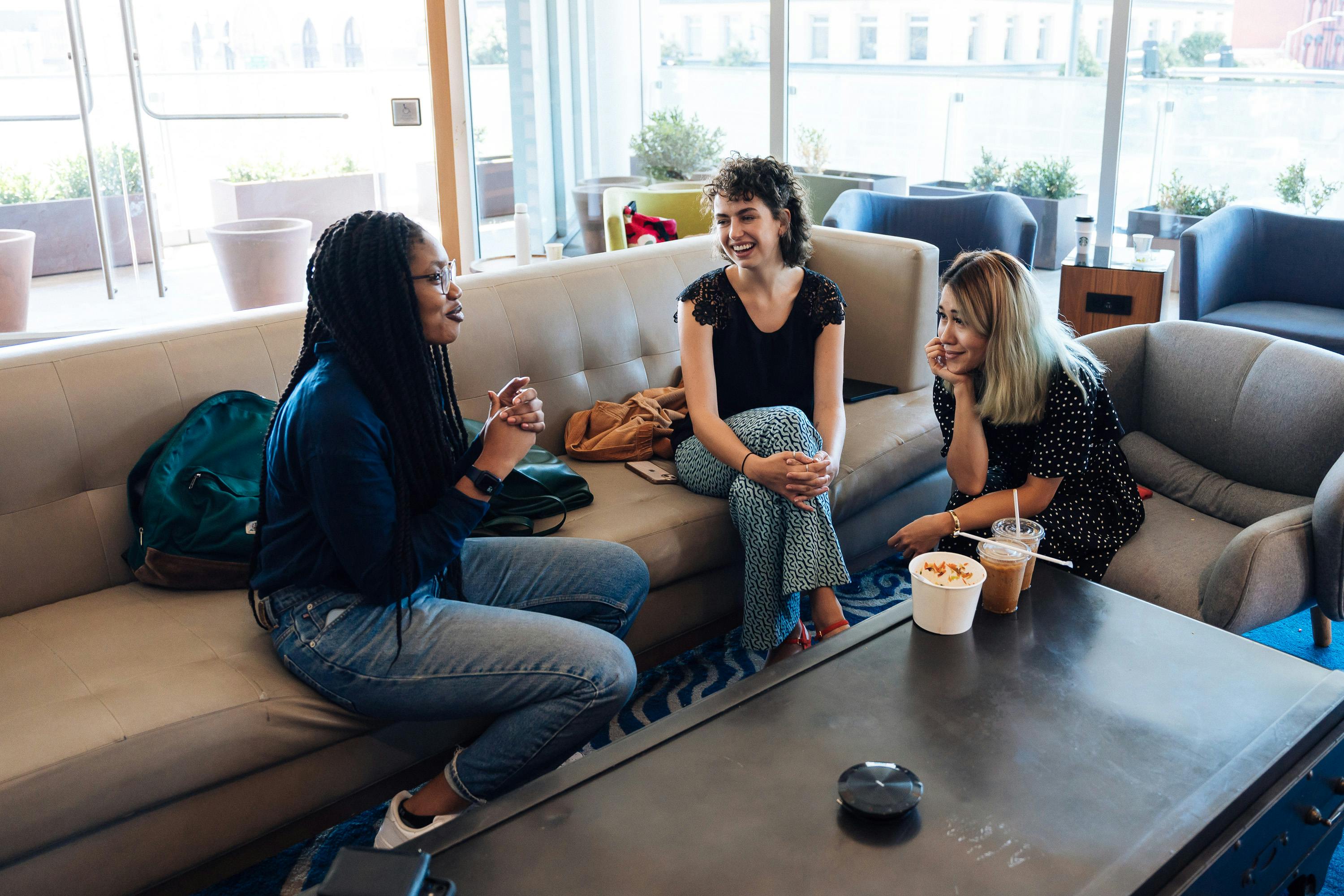 Three Girls Talking with Each Other and Smiling, Sitting on a Sofa and ...